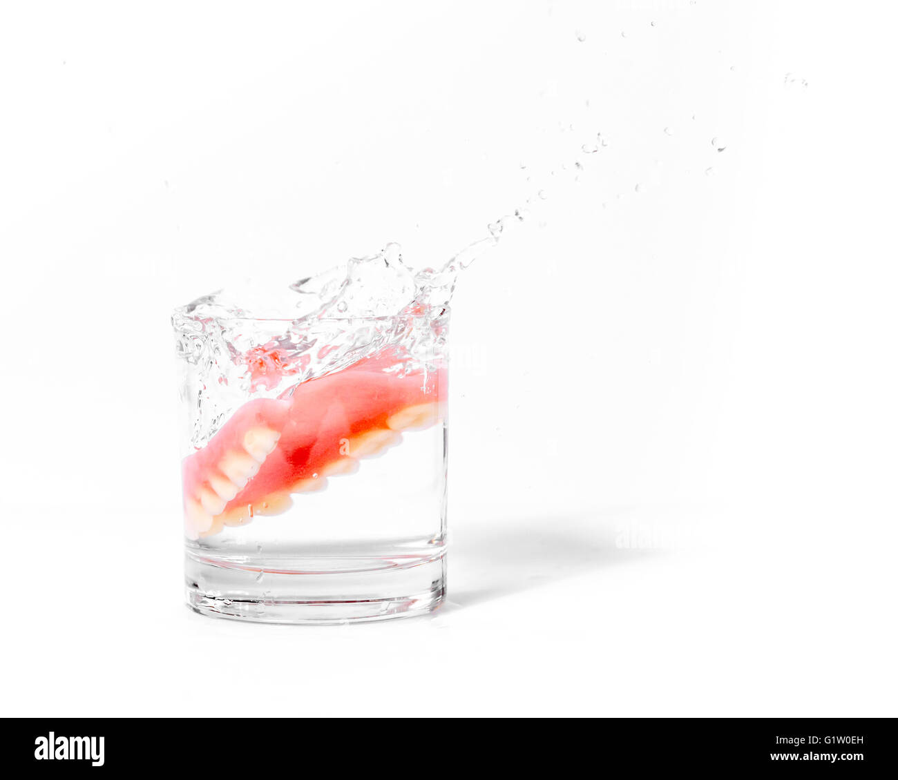 Dentures splash and falling drop into glass of water Stock Photo - Alamy