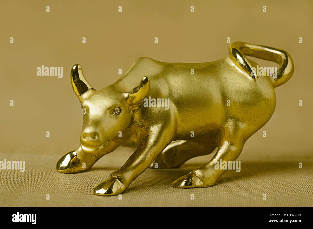 Small golden bull (miniature) on the golden background, Studio shot ...
