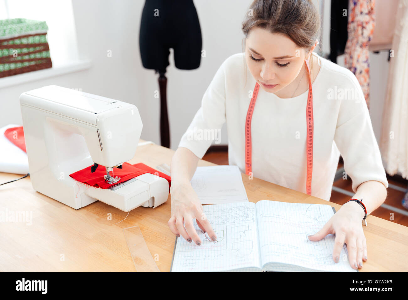 Pensive serious young woman seamstress thinking and reading notes in ...