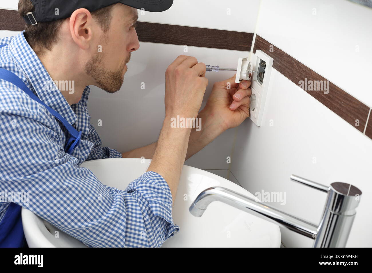 A Electrician changing a socket outlet in bathroom Stock Photo - Alamy