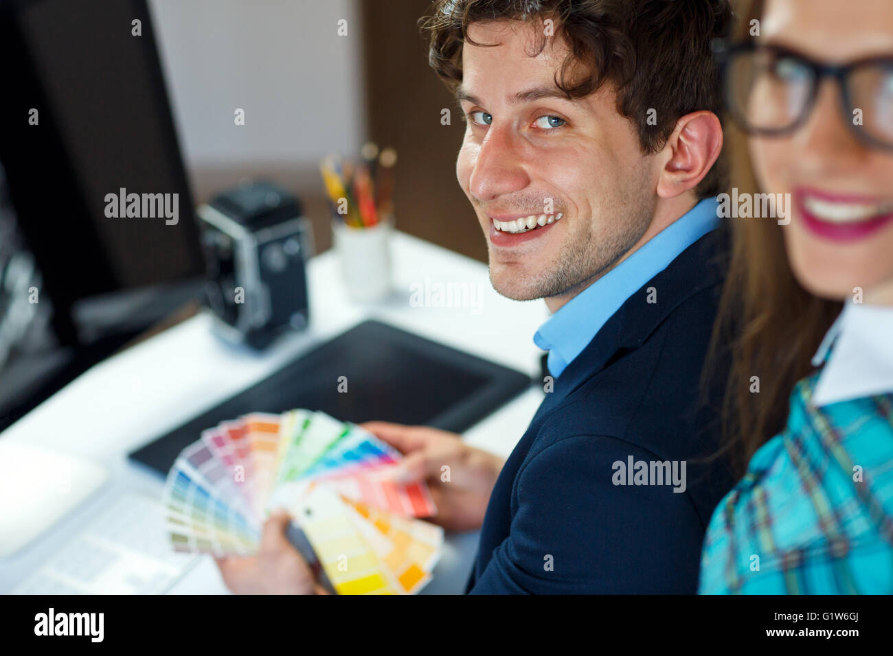 Young colleague - man and woman looking to a color paint palette at ...