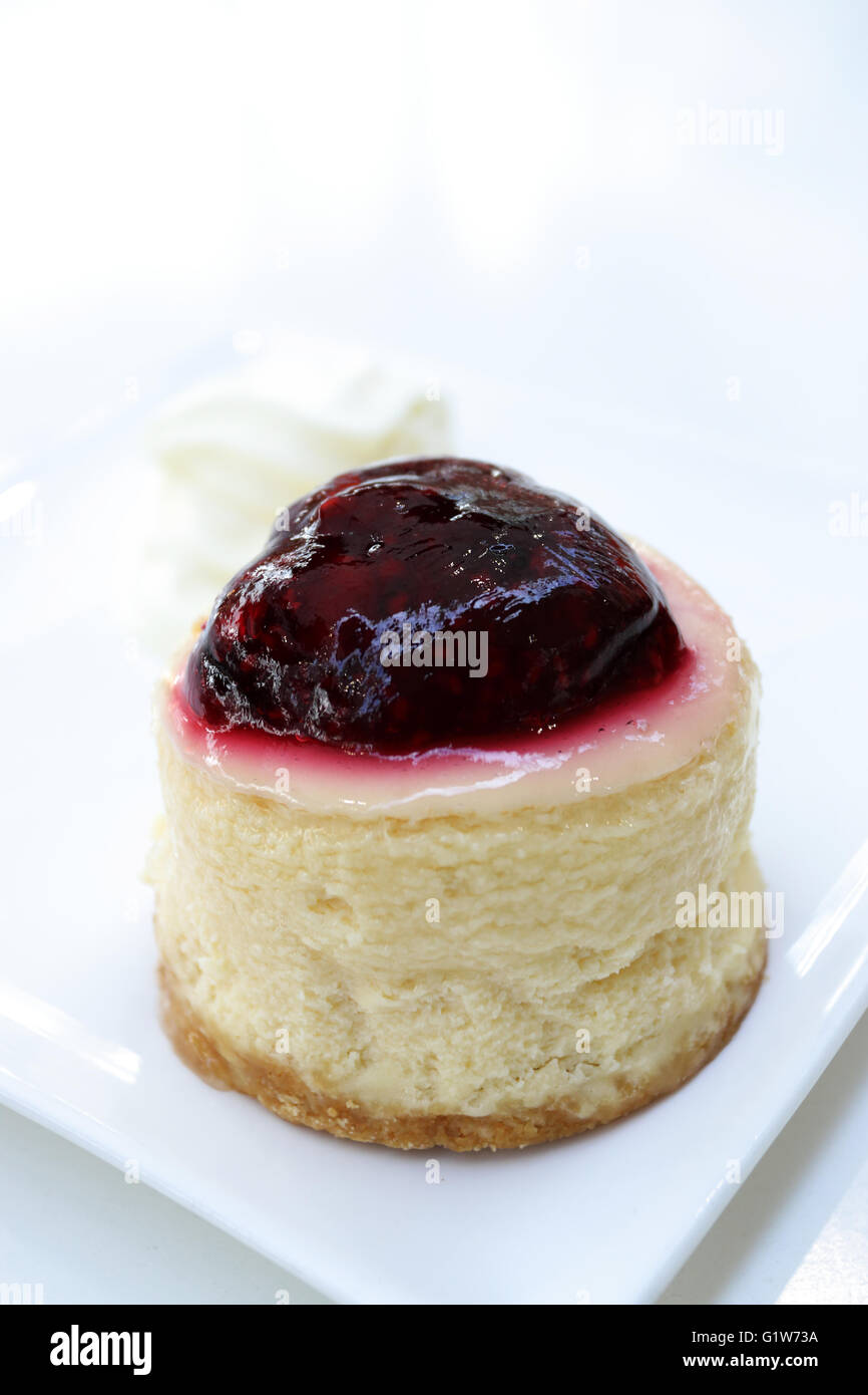 Mini cheesecake with raspberry glaze on top against white background ...