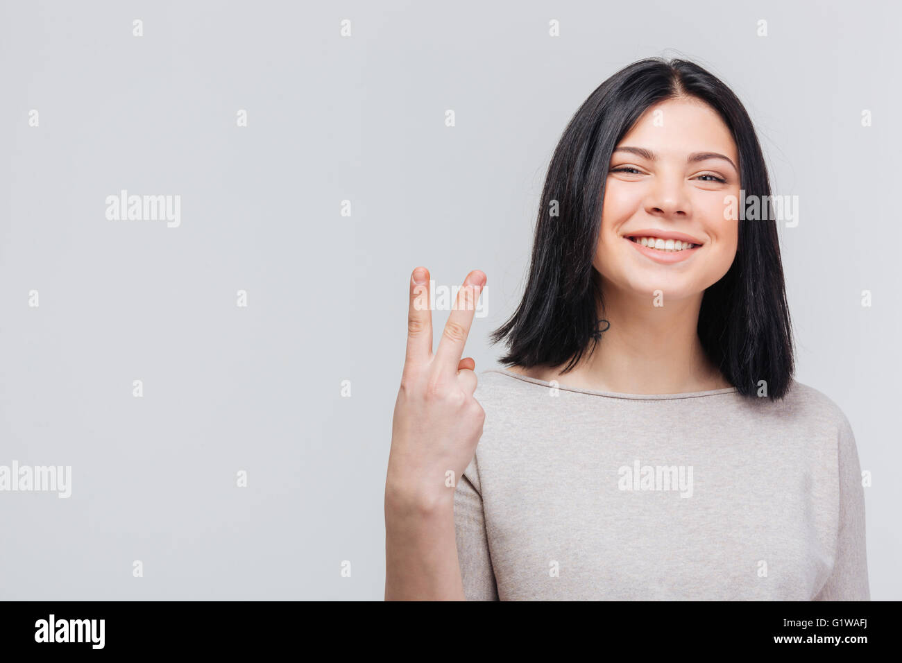 Beautiful brunette girl giving victory sign isolated on a white ...