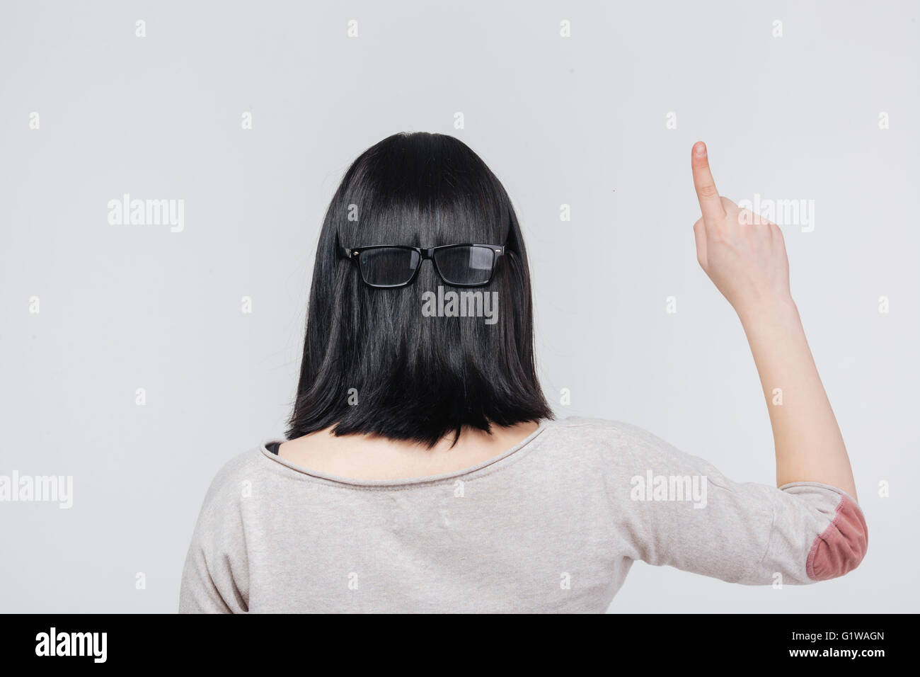 Back view portrait of a brunete girl pointing finger up isolated on a ...