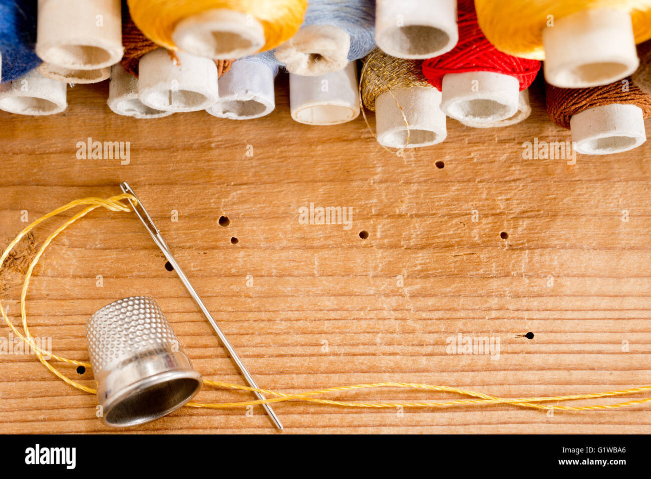 needle with thread and thimble o the wooden desk Stock Photo - Alamy