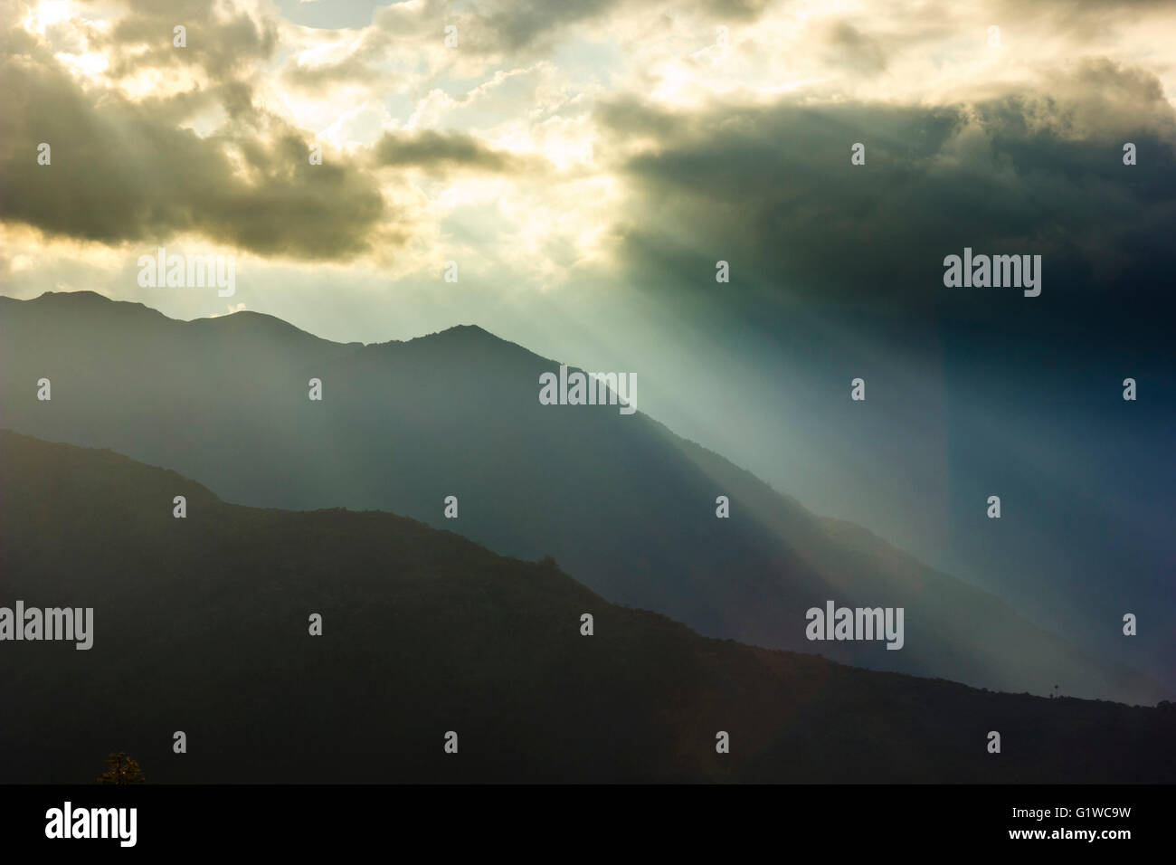 sunbeam above mountains at sunset with clouds on sky and shades on ...