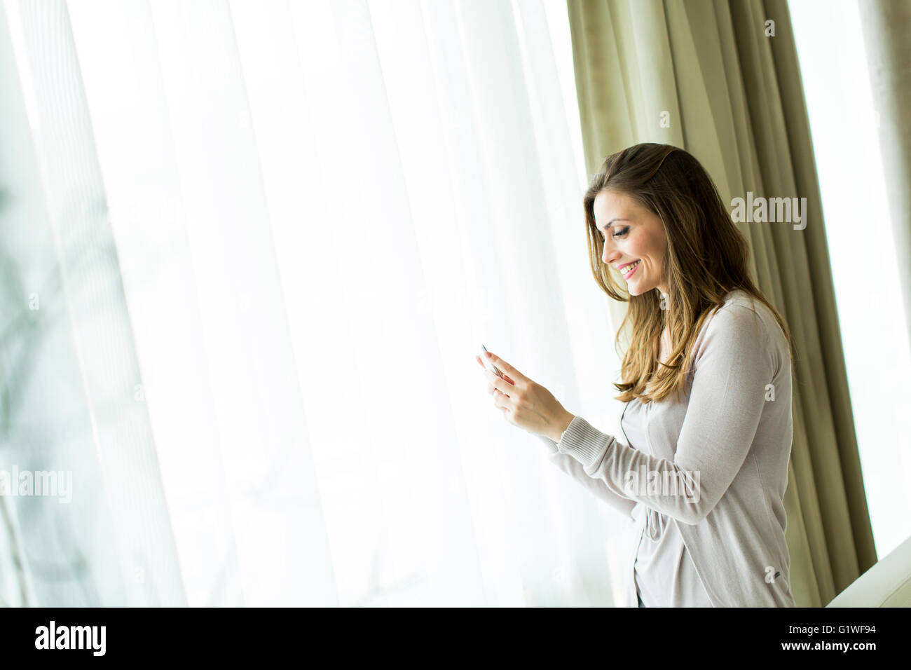 Woman with a mobile phone by the window Stock Photo - Alamy
