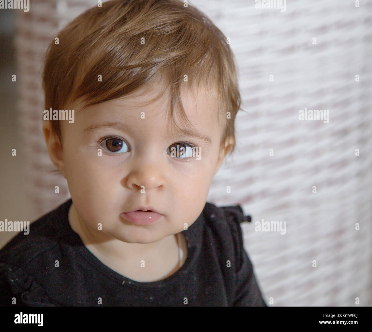 Portrait of one year old baby with brown eyes looking calmly at camera ...