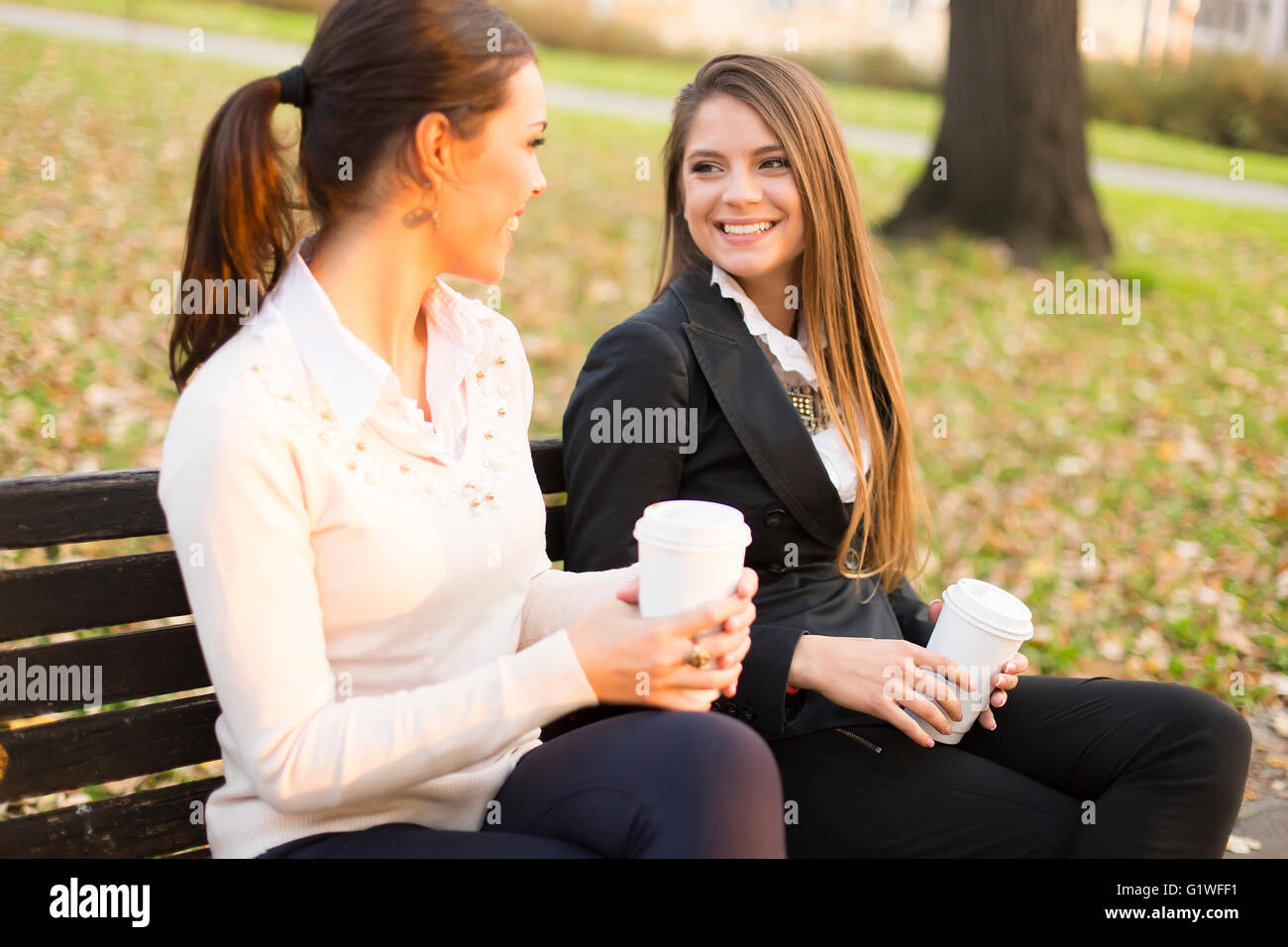 Two girls sitting on park bench hi-res stock photography and images - Alamy