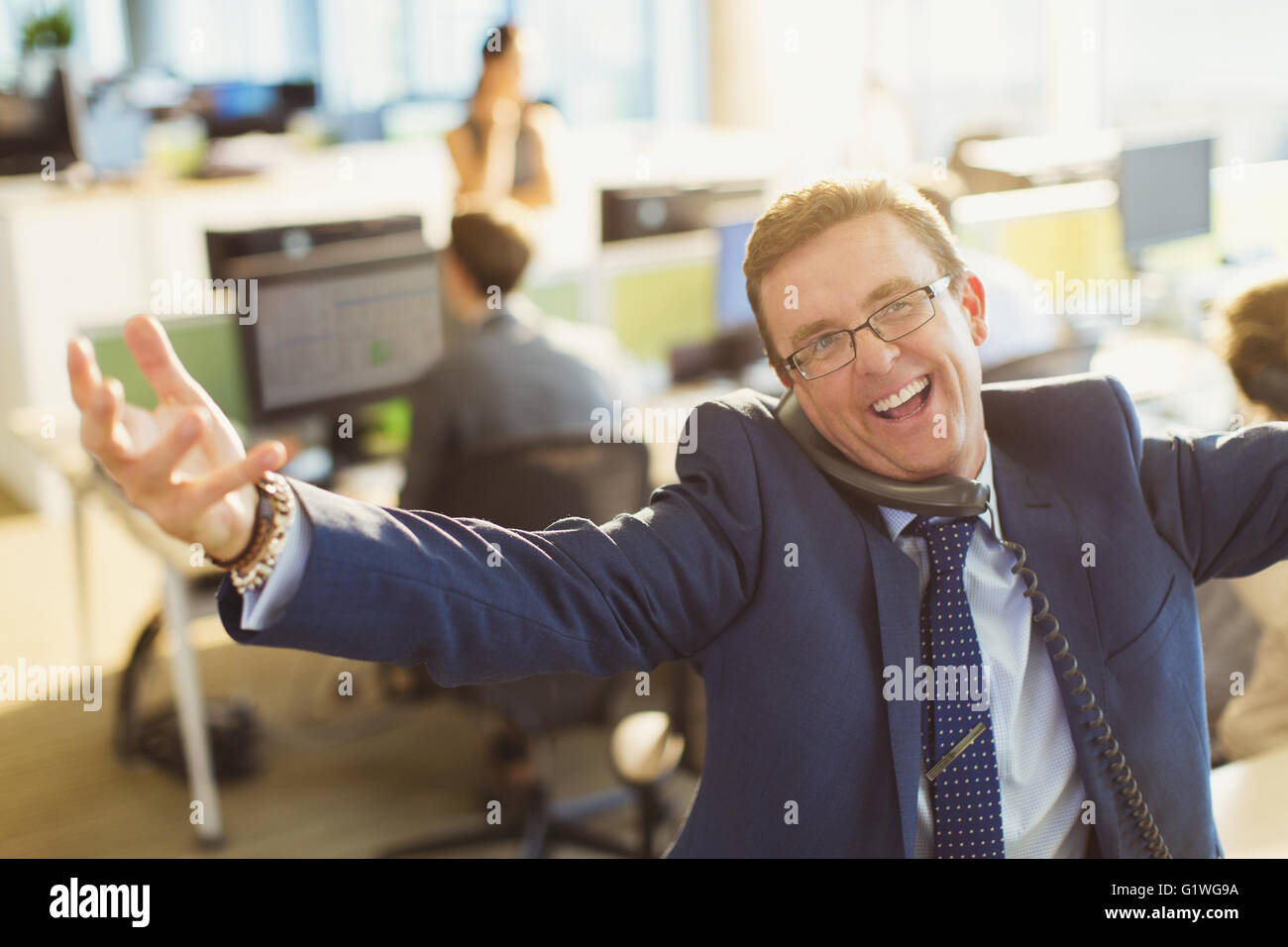 Portrait of exuberant businessman with arms outstretched talking on ...
