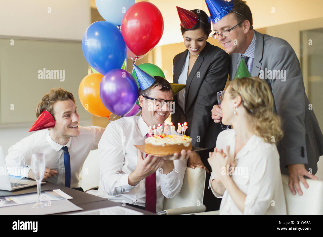 Colleagues presenting businesswoman with birthday cake in conference ...
