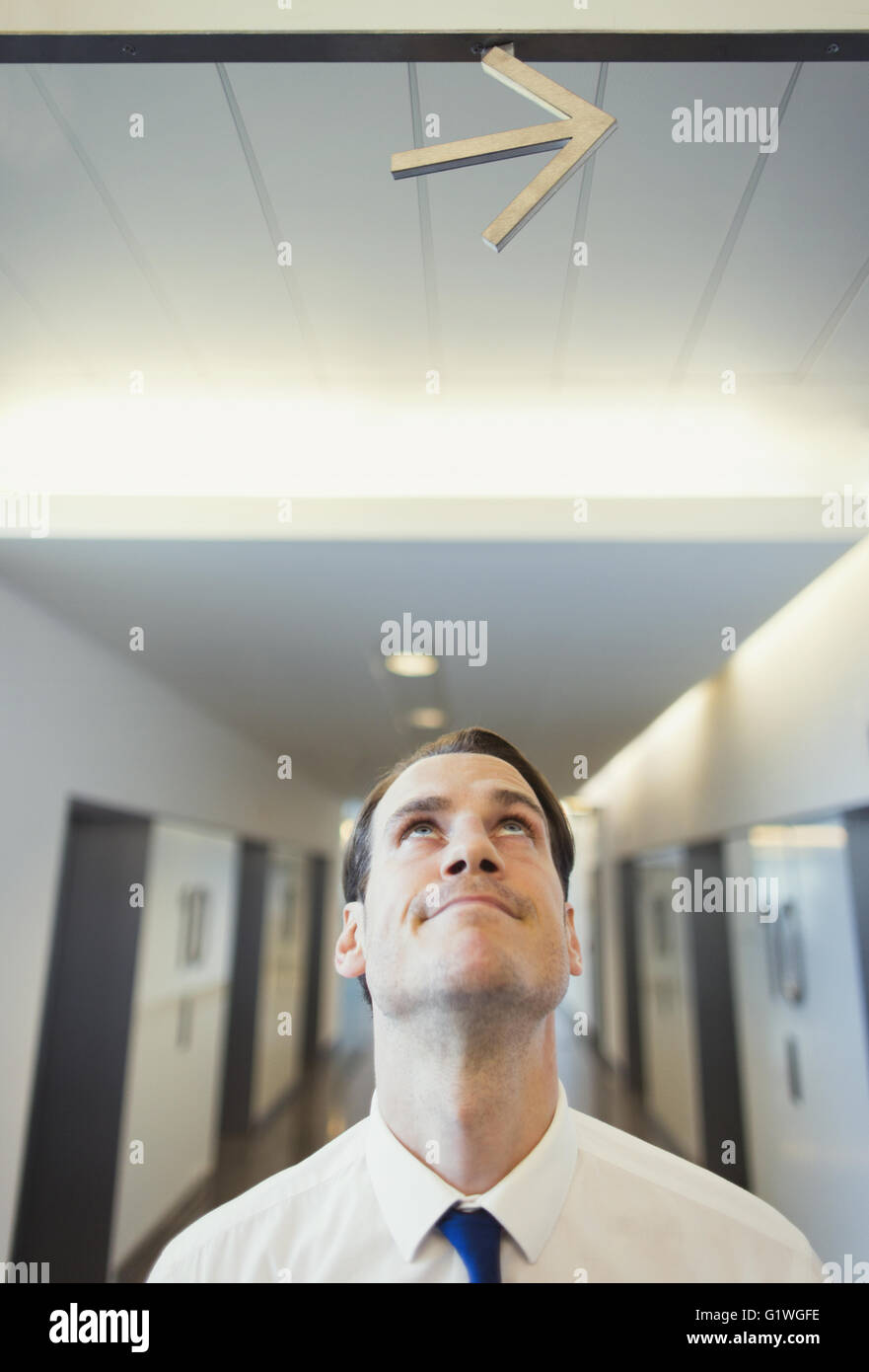 Businessman looking up at arrow overhead Stock Photo - Alamy