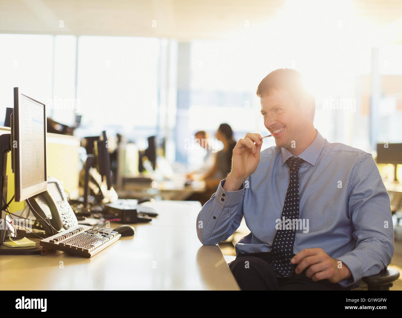 Smiling businessman at computer in sunny office Stock Photo - Alamy