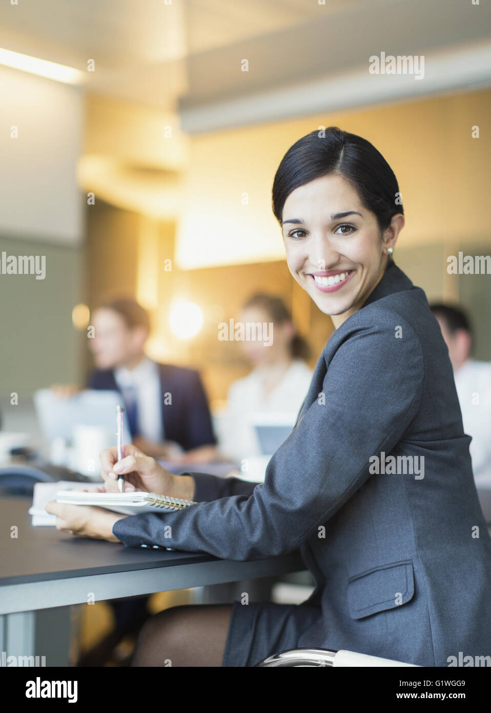 Portrait smiling businesswoman taking notes in conference room meeting ...