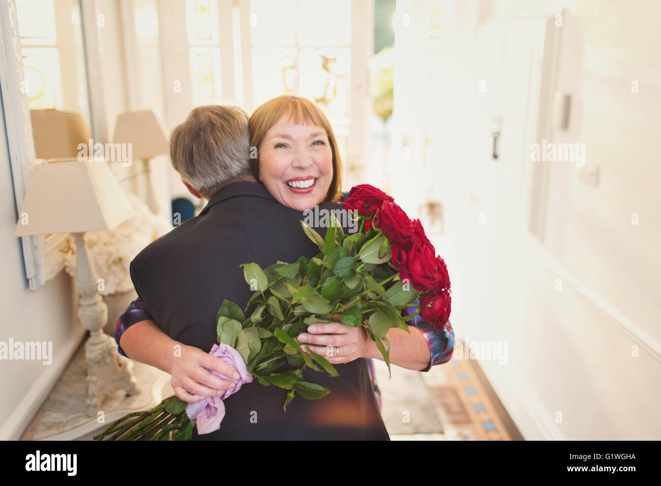 Happy women receiving rose bouquet and hugging husband Stock Photo - Alamy