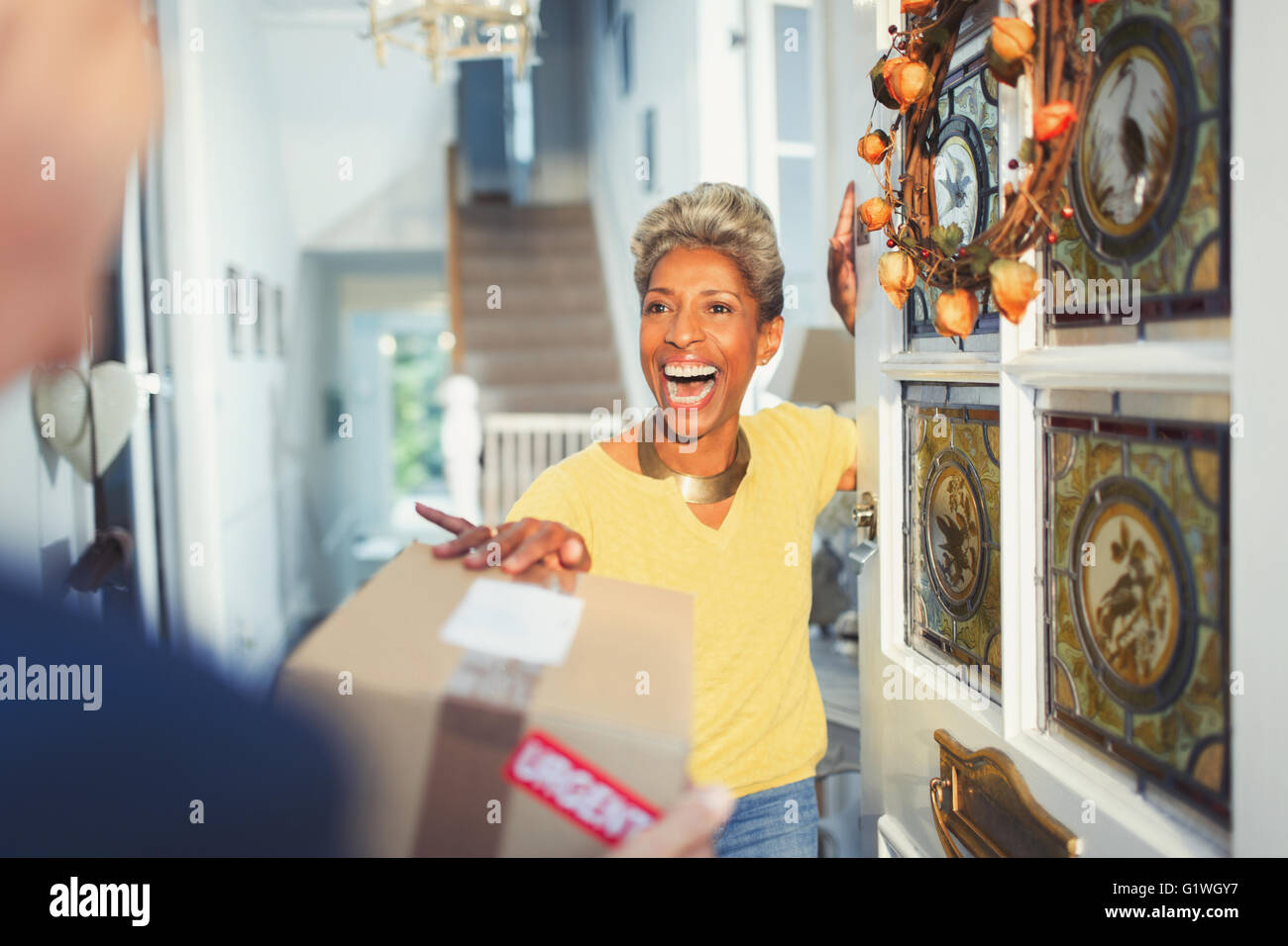 Enthusiastic woman receiving package delivery at front door Stock Photo ...
