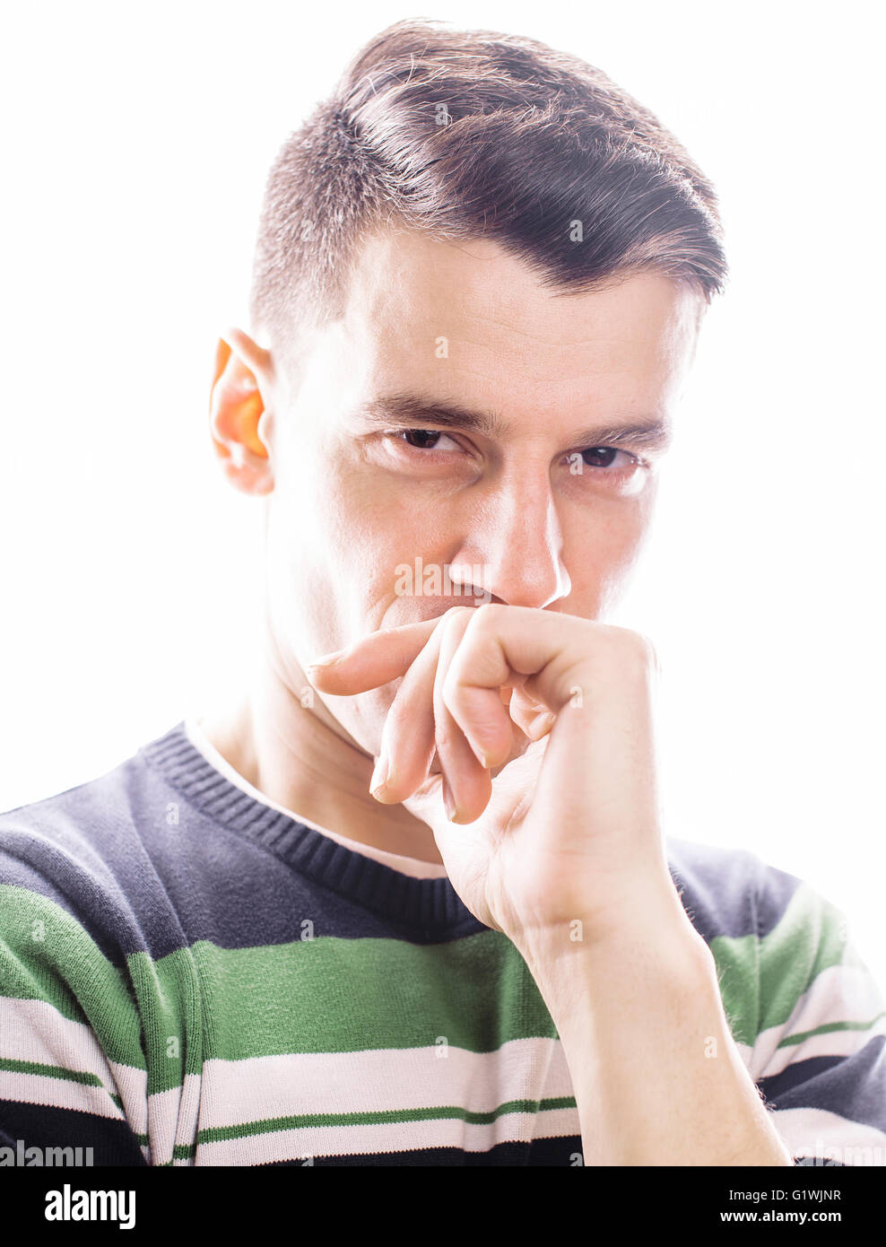 Portrait of a smart serious young man standing against white background ...