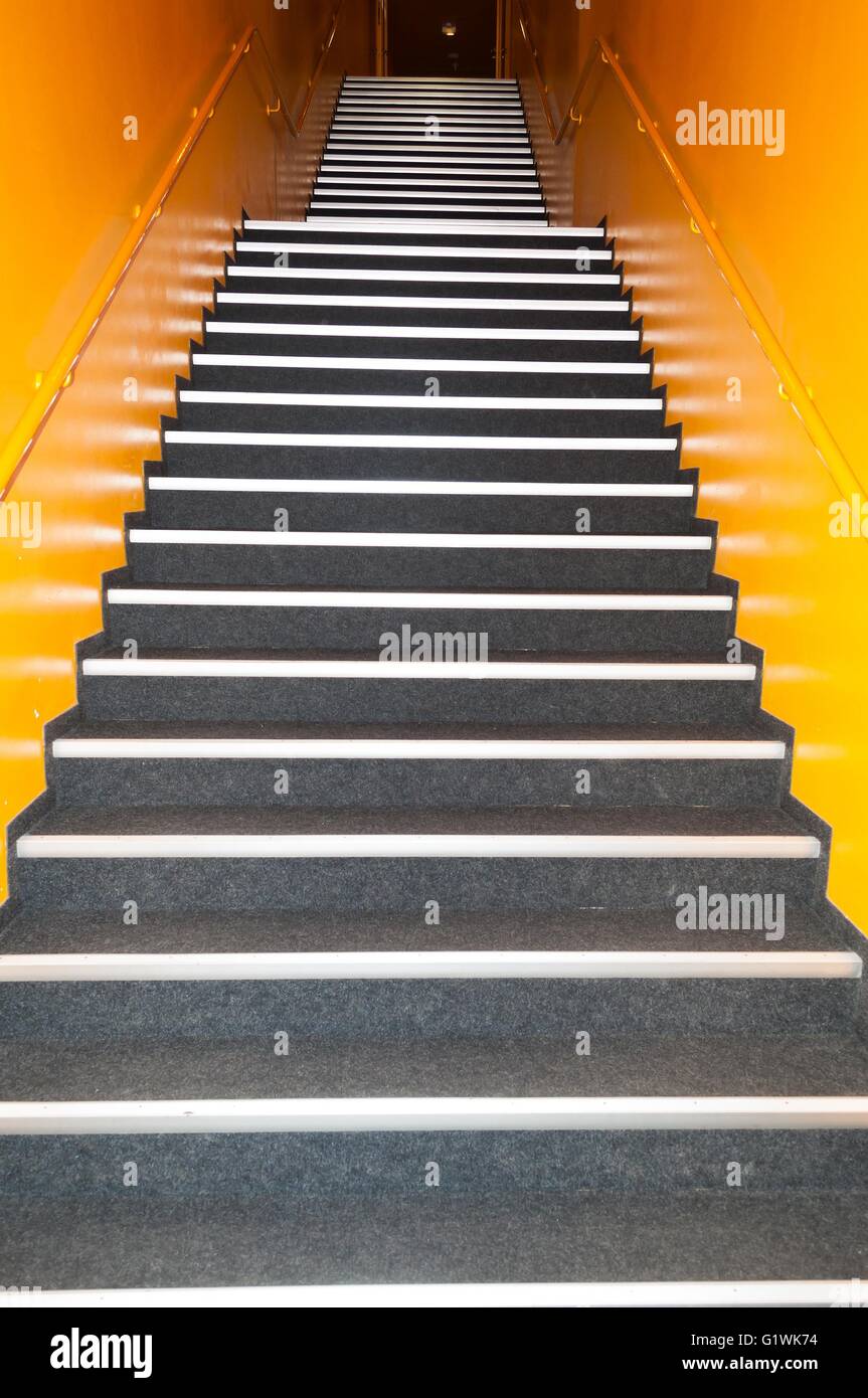 Long gray stairs with many steps in a high building with yellow wall ...