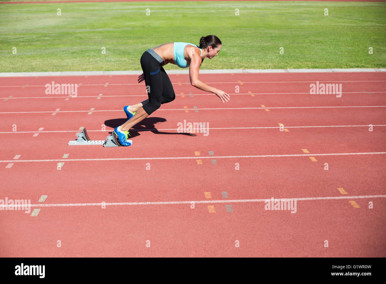 Female athlete running from starting blocks Stock Photo - Alamy