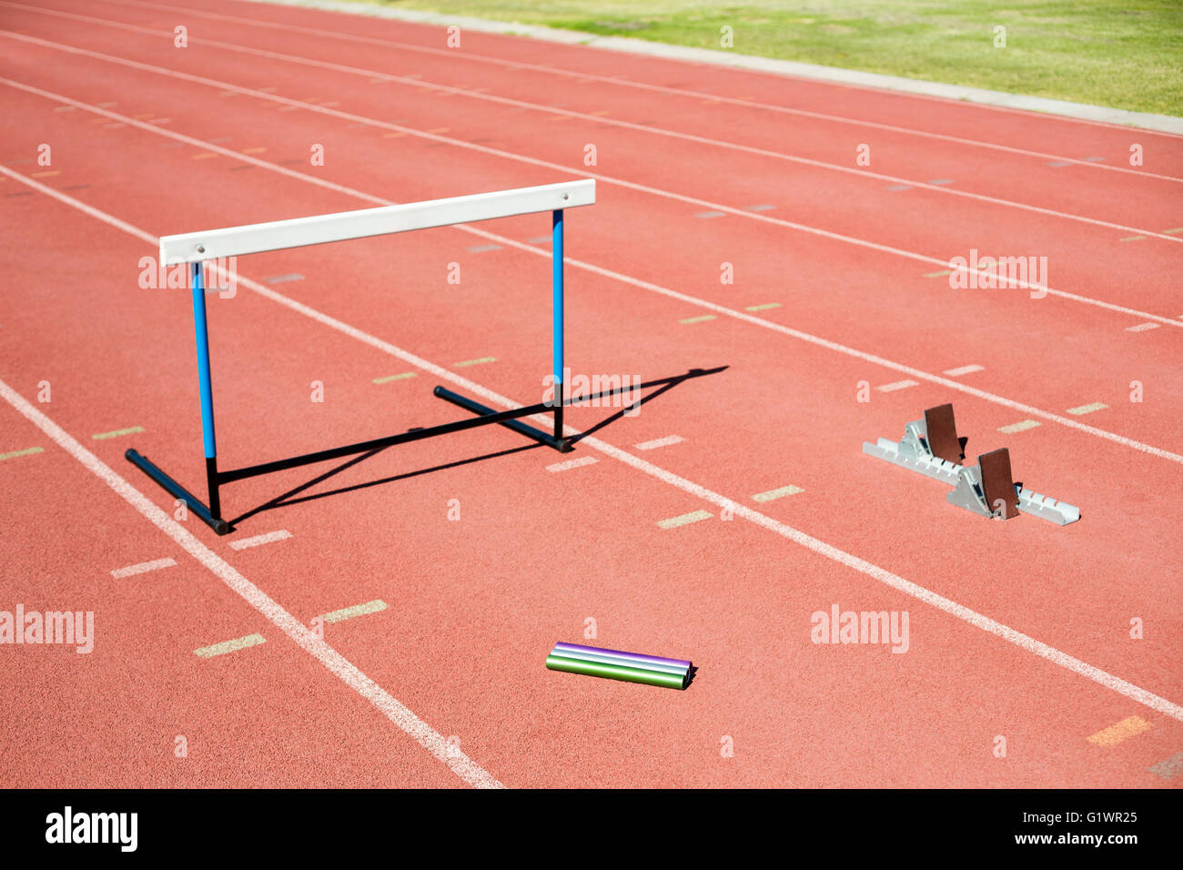 Hurdle, relay baton and a starting block kept on a running track Stock ...