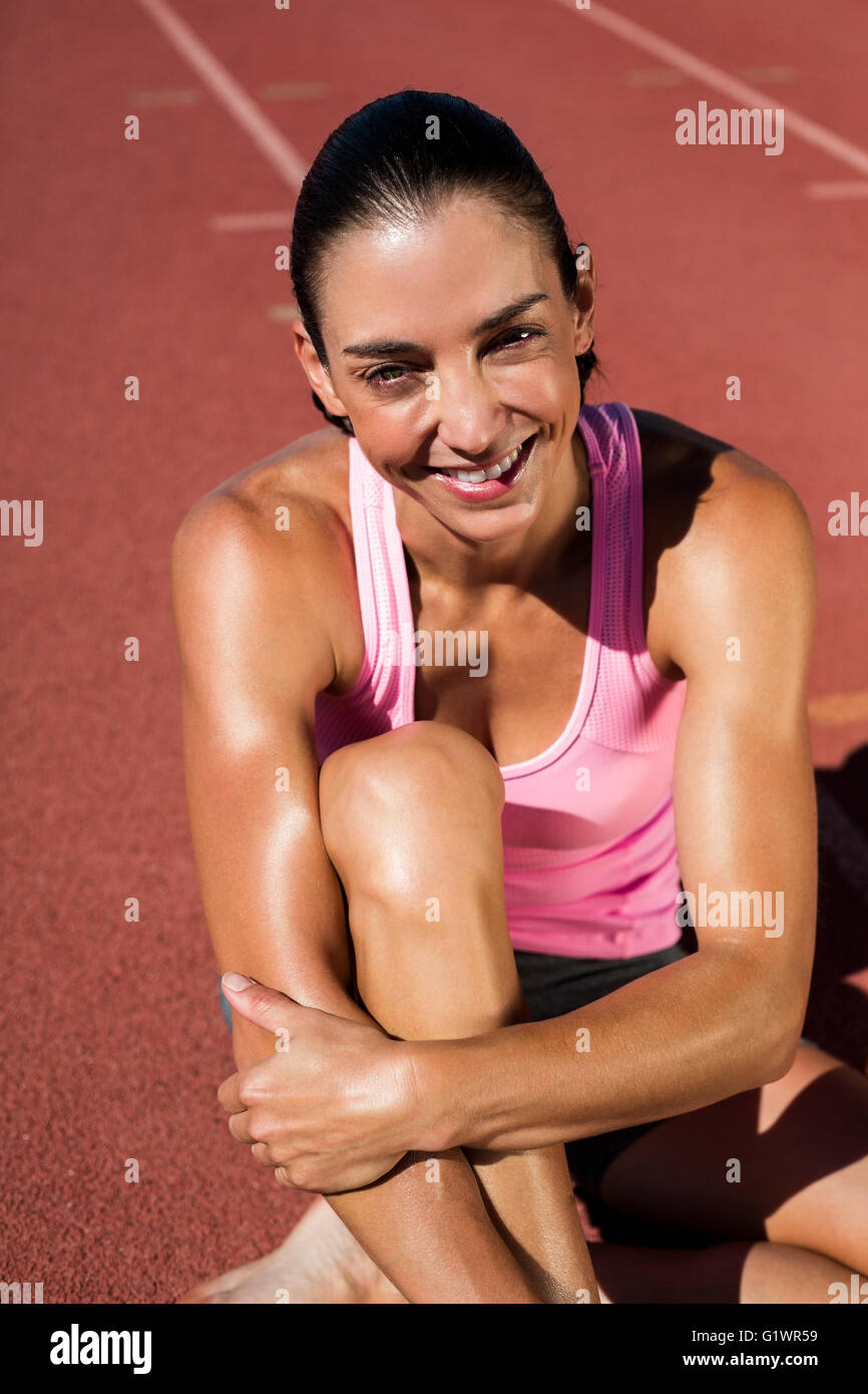 Portrait of female athlete sitting on running track Stock Photo - Alamy