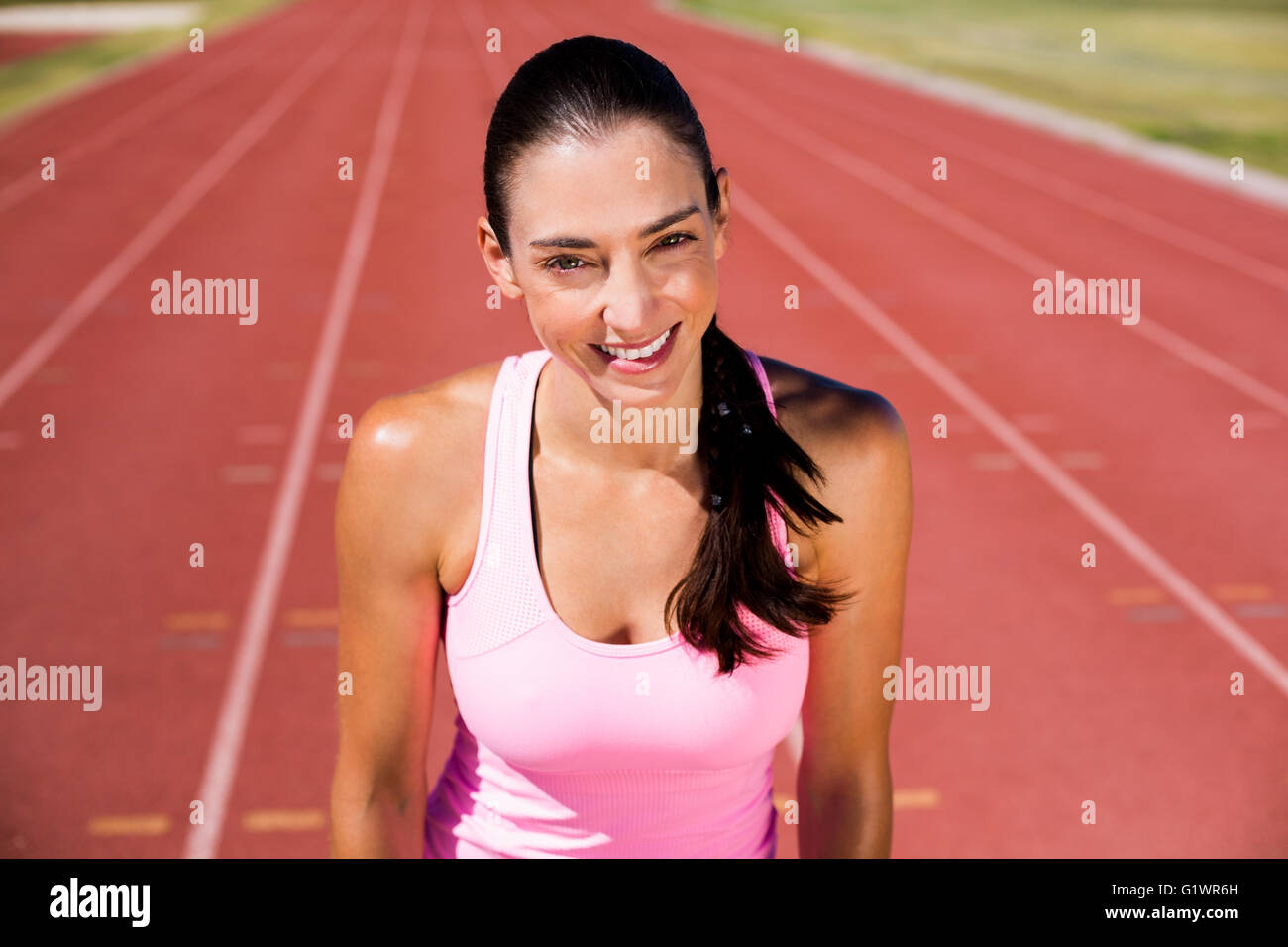 Portrait of happy female athlete standing on running track Stock Photo ...
