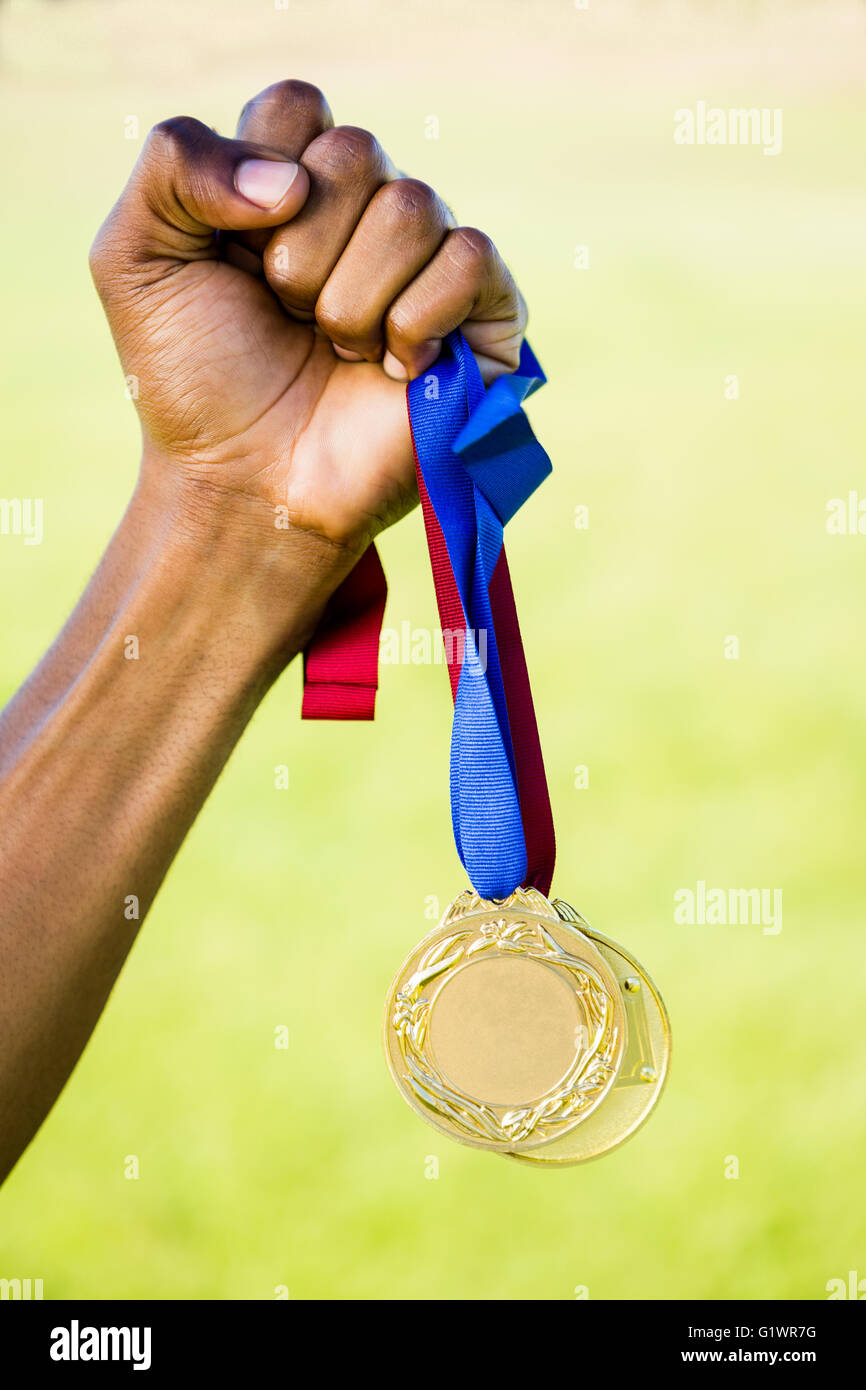Athletes hand holding gold medal after victory Stock Photo - Alamy