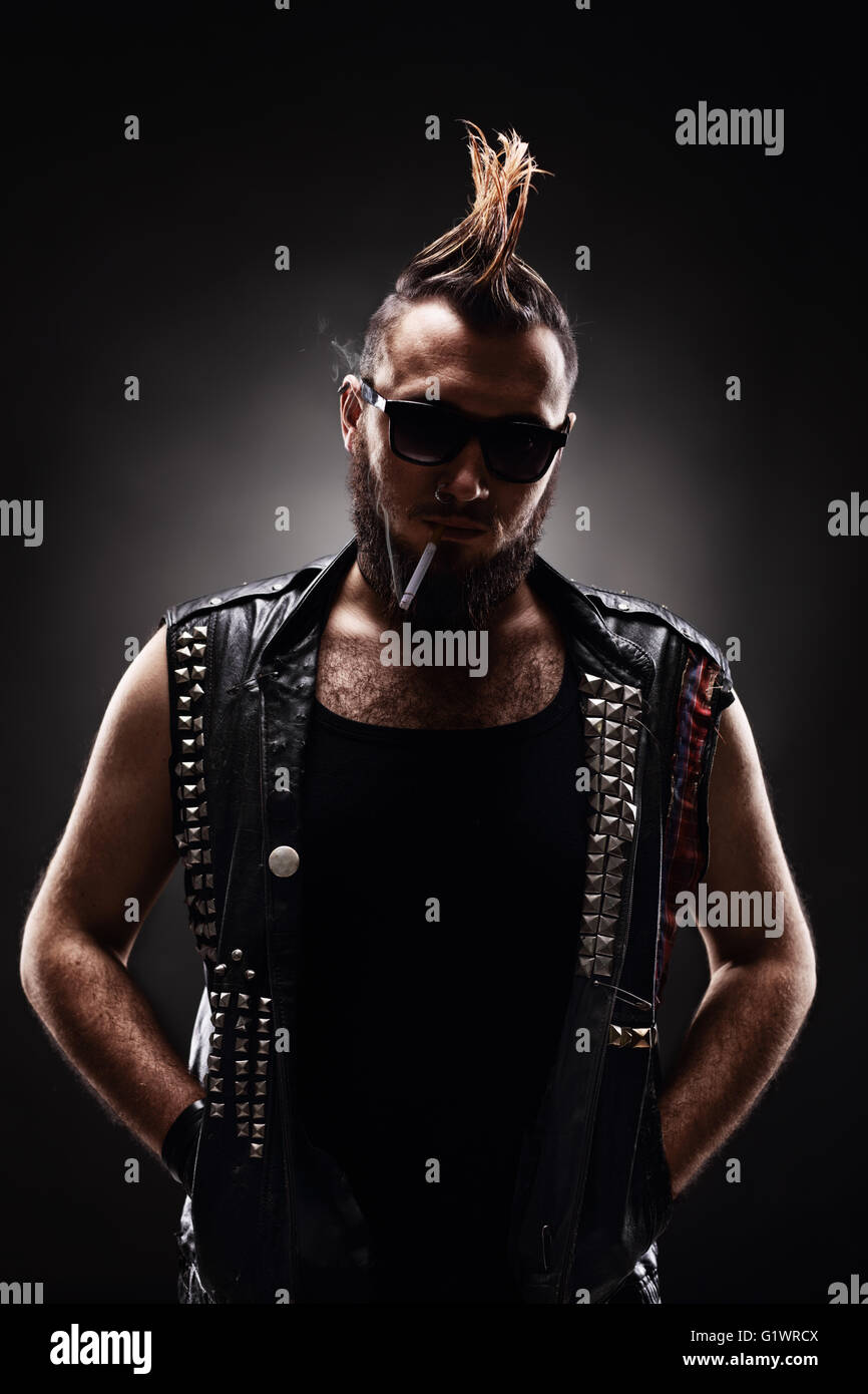 Vertical shot of a male punk with Mohawk hairstyle smoking a cigarette ...