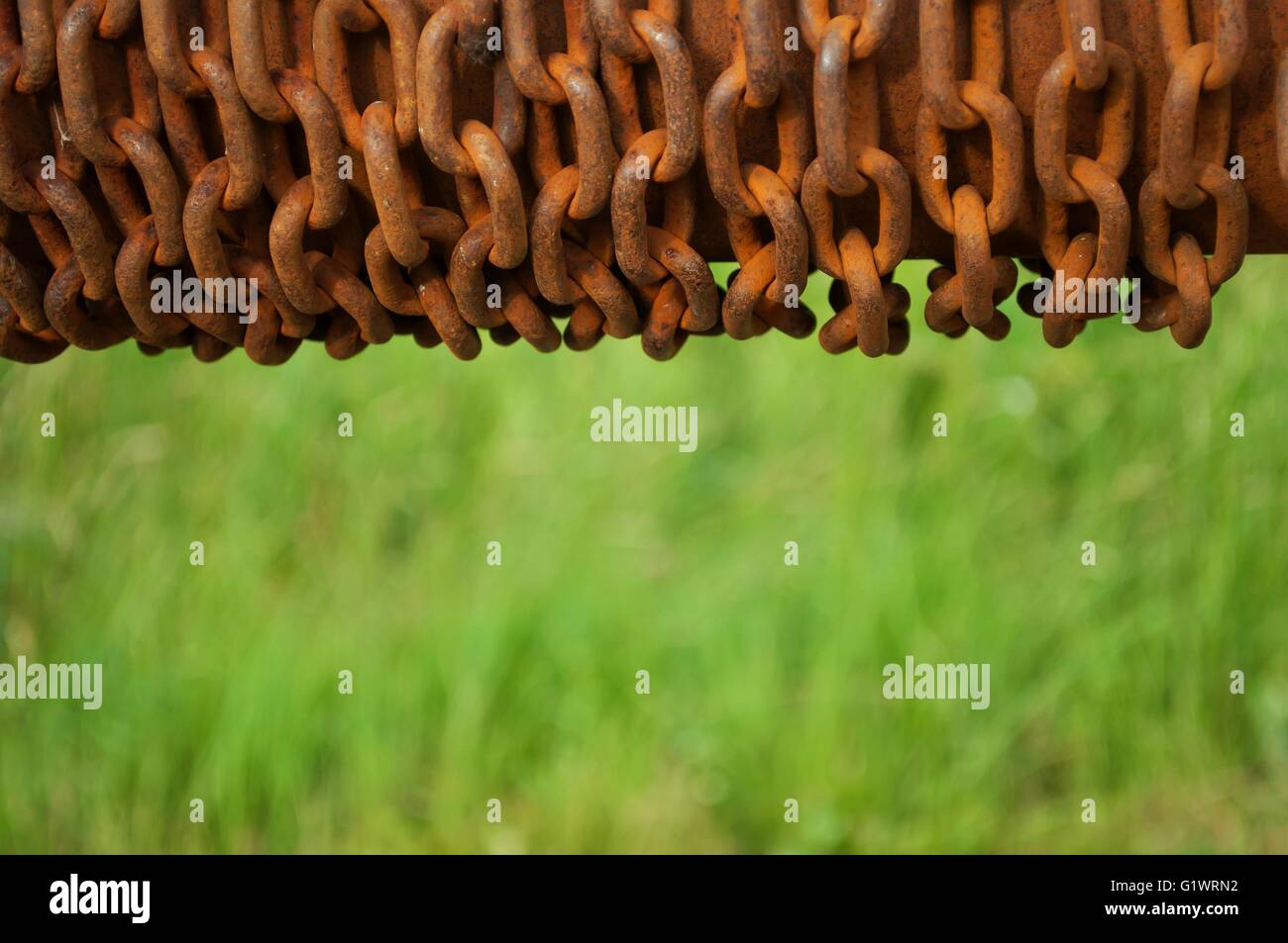 Rolled rusty chain with blurred green natural background. Space in ...
