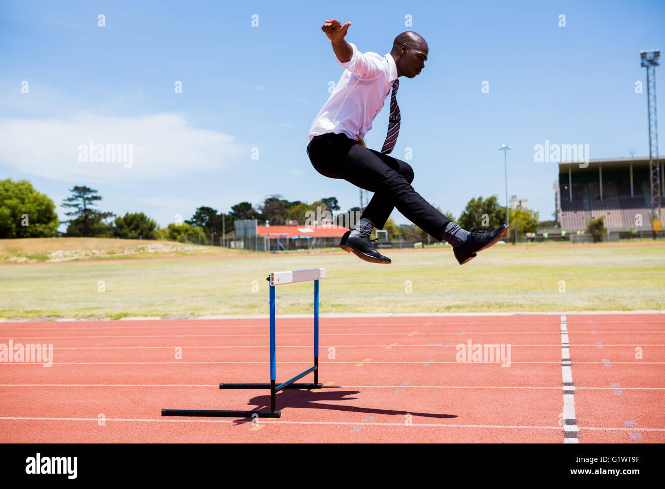 Businessman jumping a hurdle while running Stock Photo - Alamy