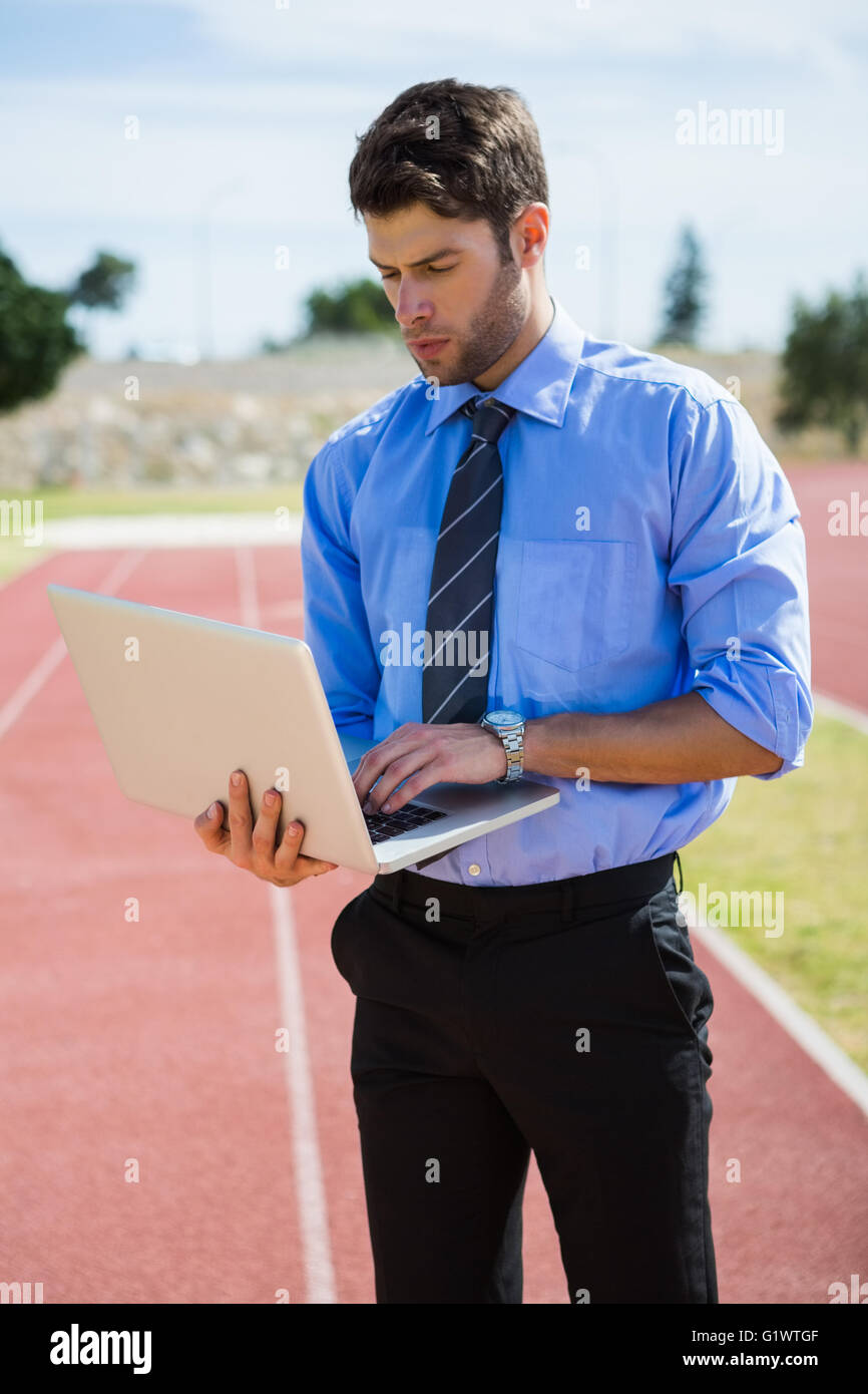 Businessman using a laptop on the running track Stock Photo - Alamy