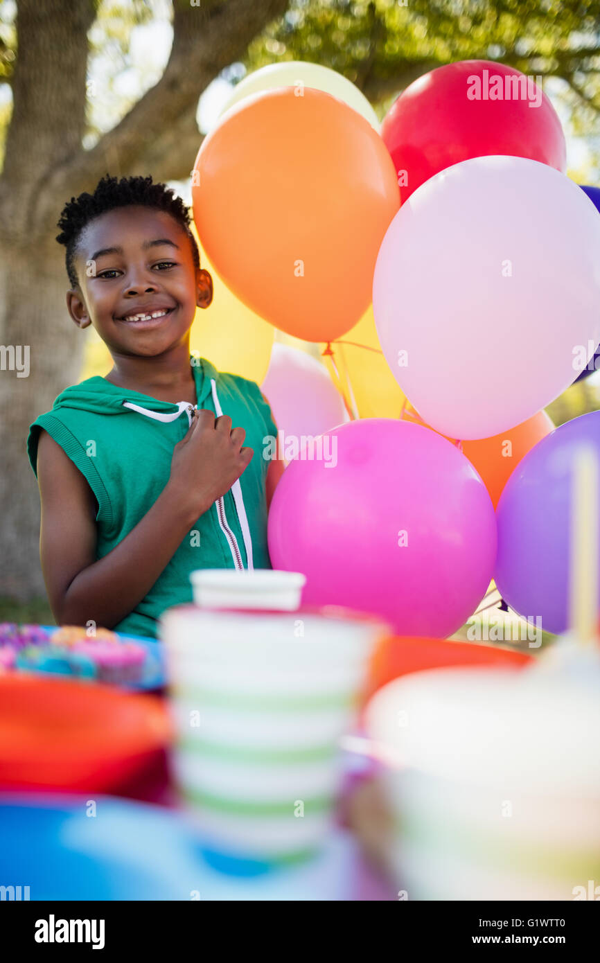 Cute boy smiling and posing next to balloon during a birthday party ...