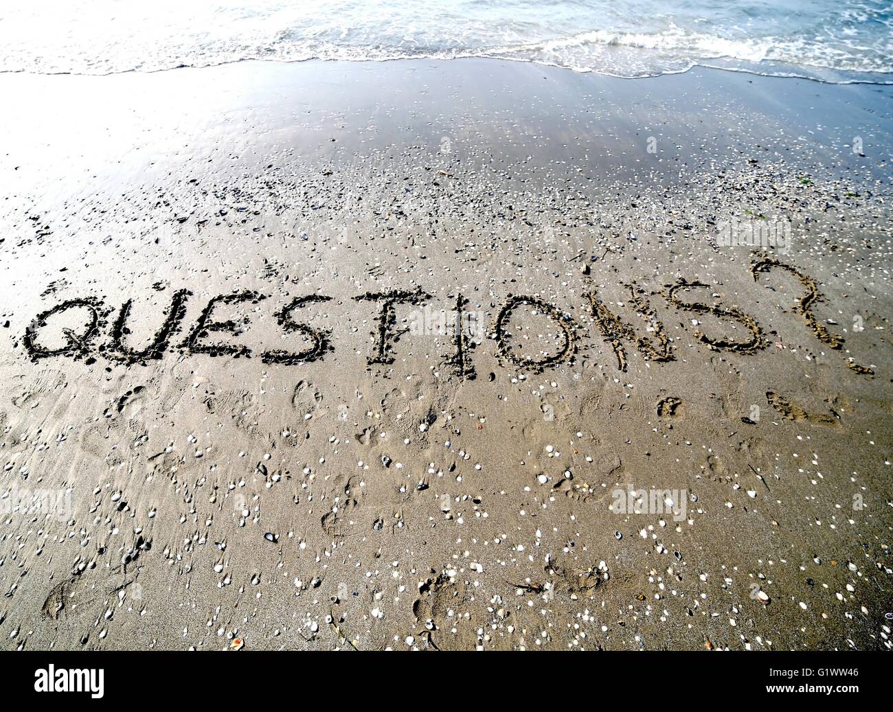 QUESTIONS written in the wet sand of the beach Stock Photo - Alamy
