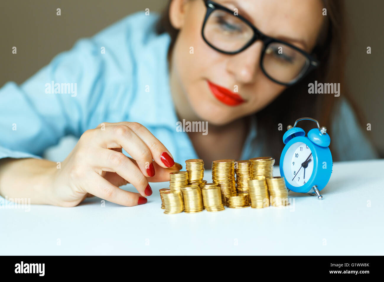 Saving, woman stacking gold coins into columns Stock Photo - Alamy