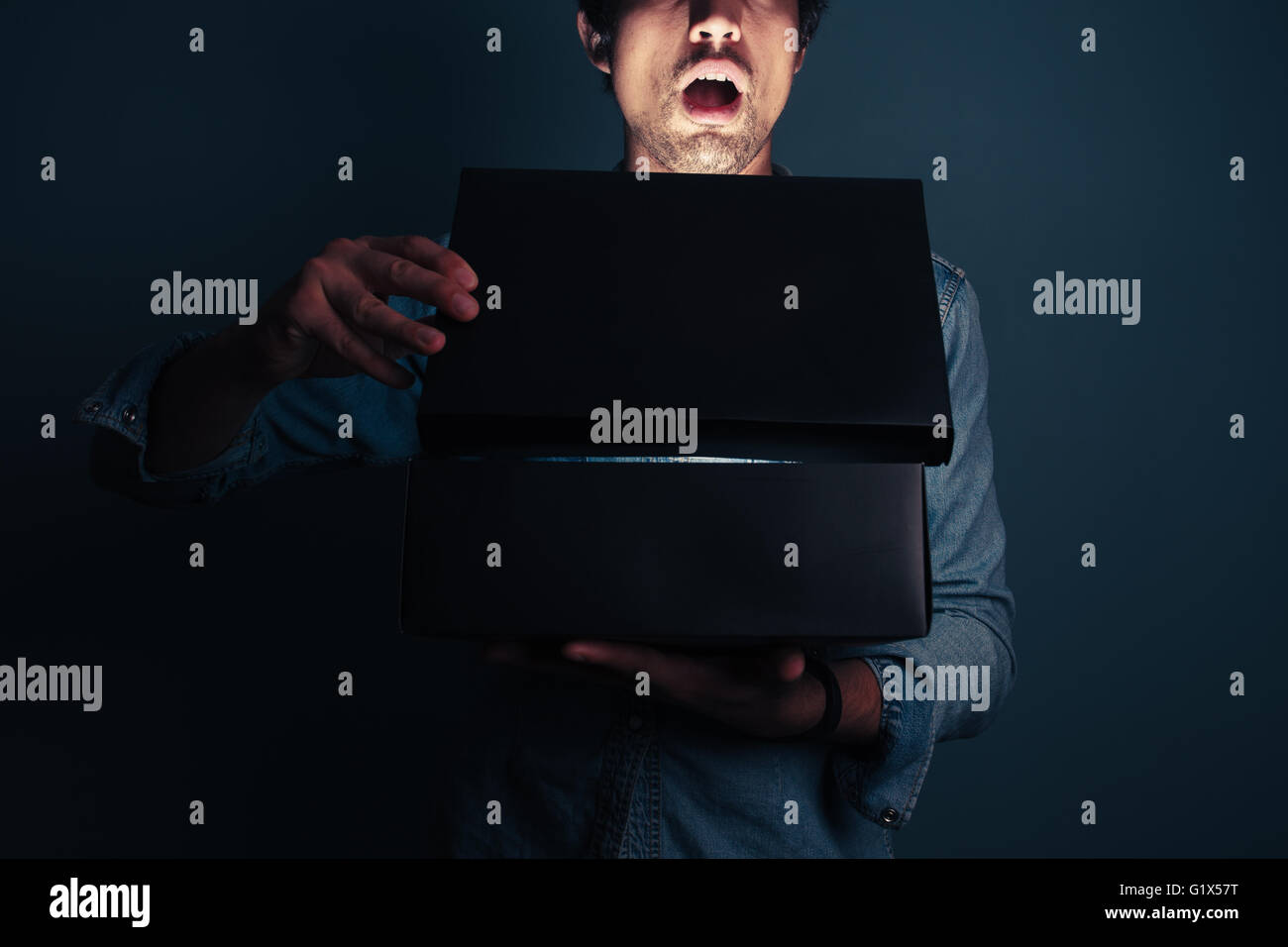 A young man is opening a box with something exciting inside it Stock ...