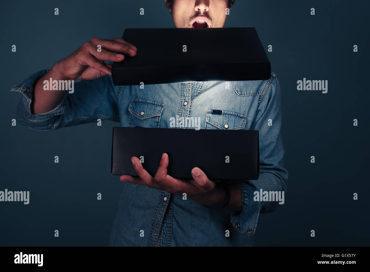 A young man is opening a box with something exciting inside it Stock ...