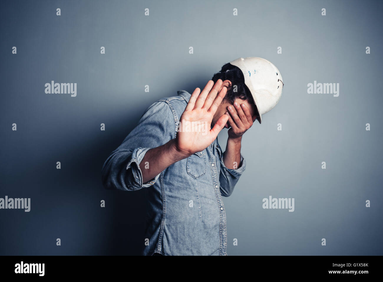 An ashamed blue collar worker is hiding his face Stock Photo - Alamy