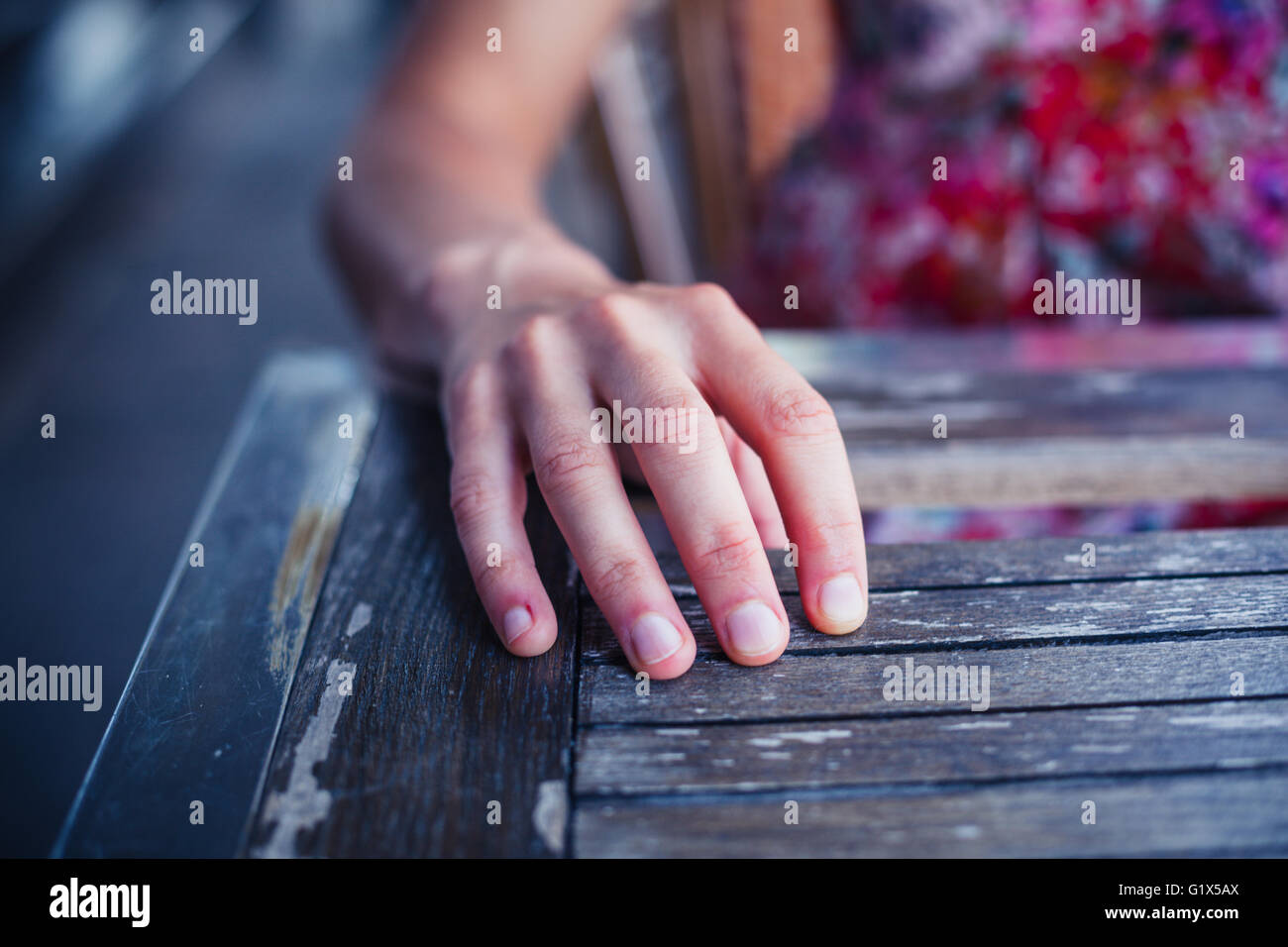 A young woman is resting her hand on a table outside Stock Photo - Alamy