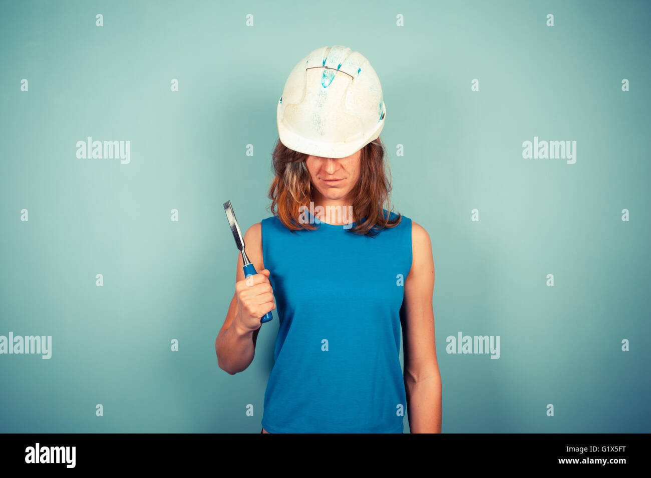 A young female builder is holding a chisel Stock Photo - Alamy