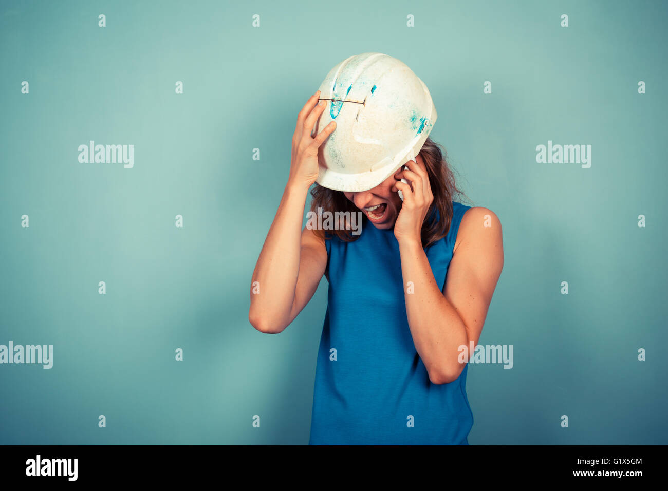 A young female builder wearing a hard hat is talking on the phone Stock ...