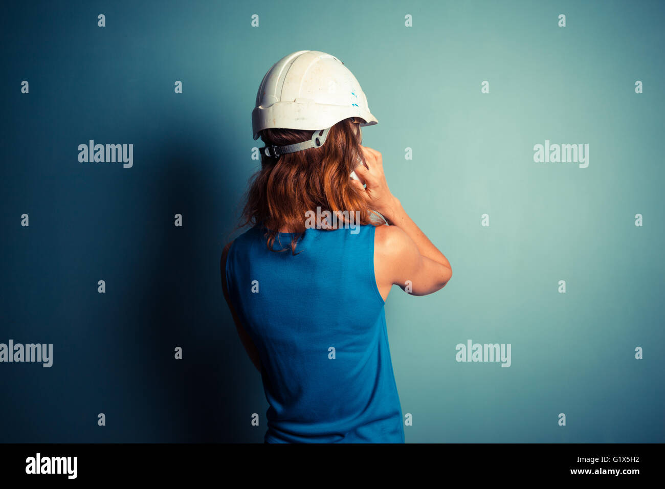 A young female builder wearing a hard hat is talking on the phone Stock ...