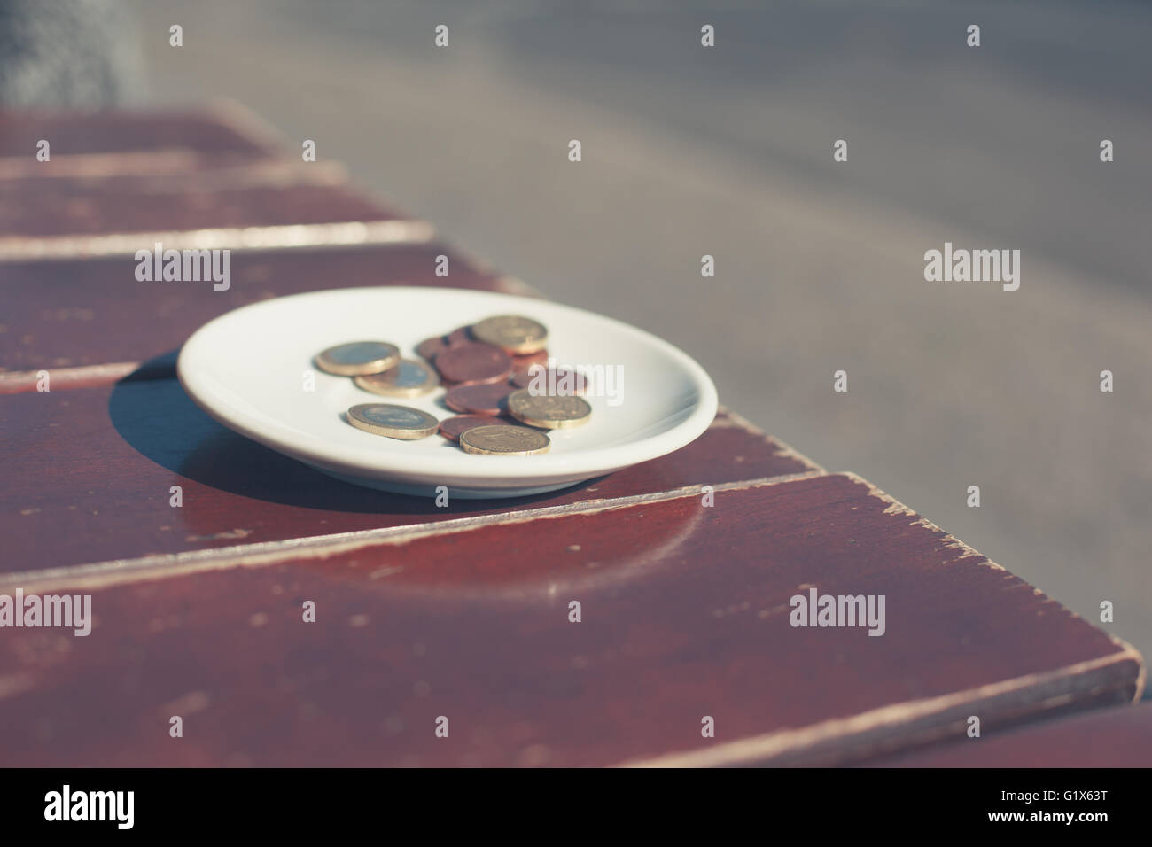 Coins on a saucer outside on a cafe table Stock Photo - Alamy
