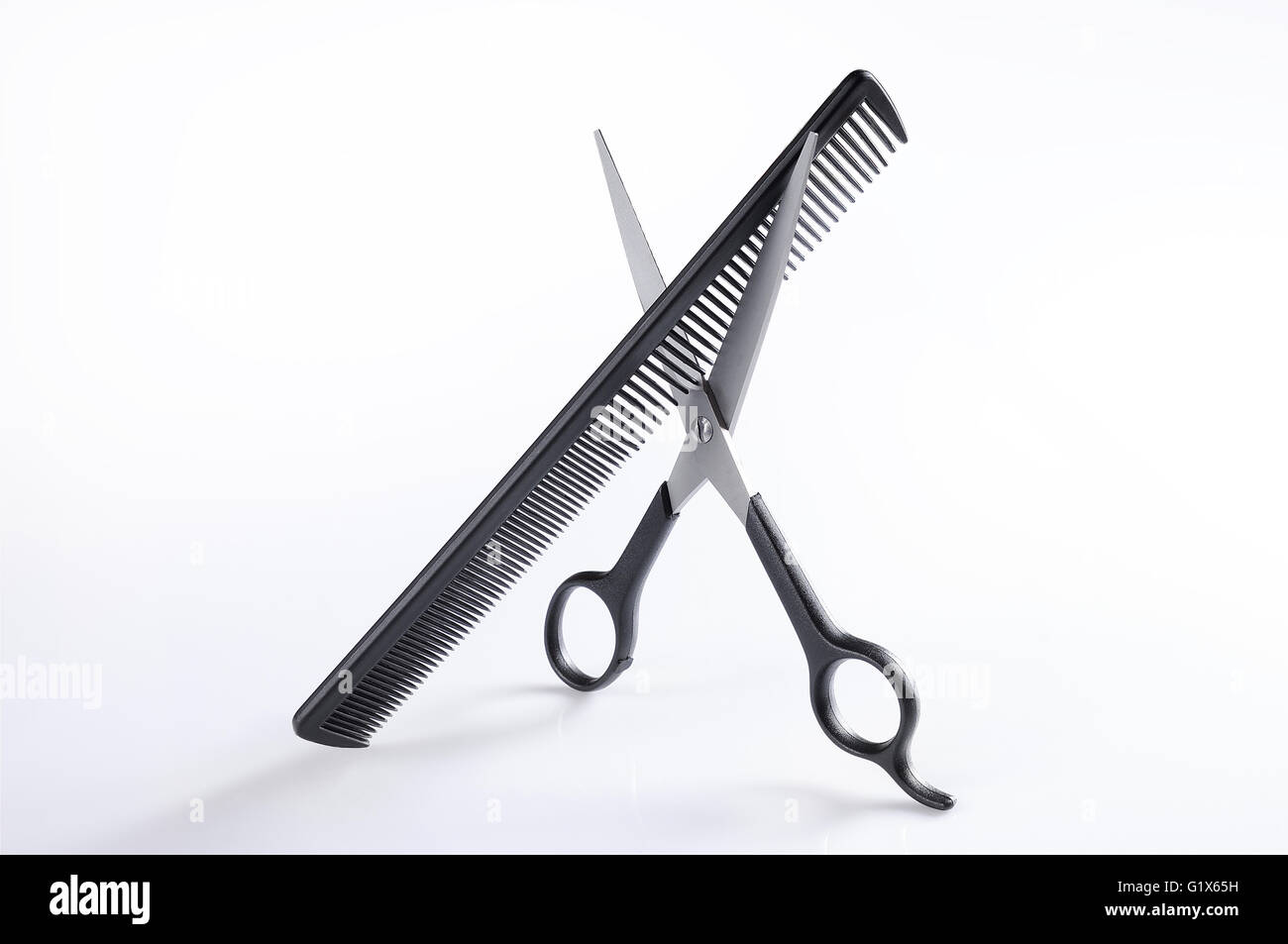 Barber scissors and comb standing on a white table, overview isolated ...