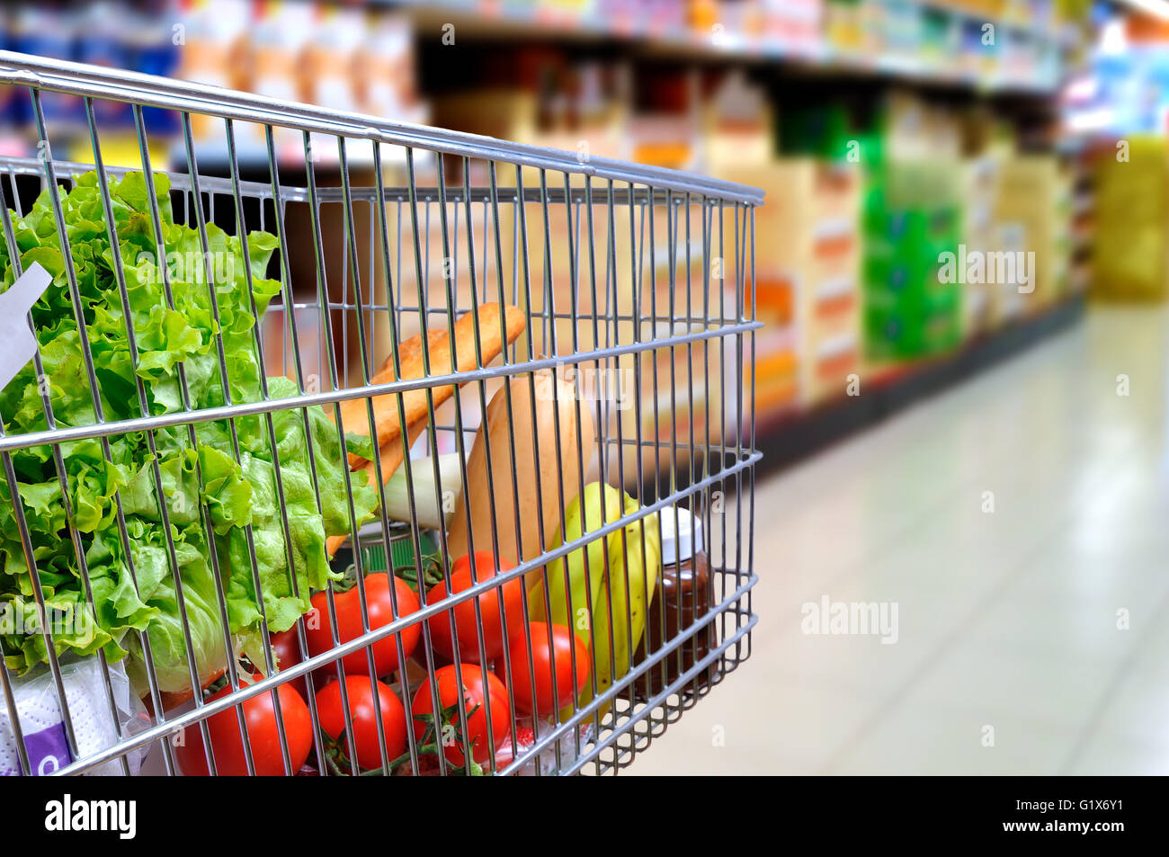 Shopping cart full of food in the supermarket aisle. Side tilt view ...