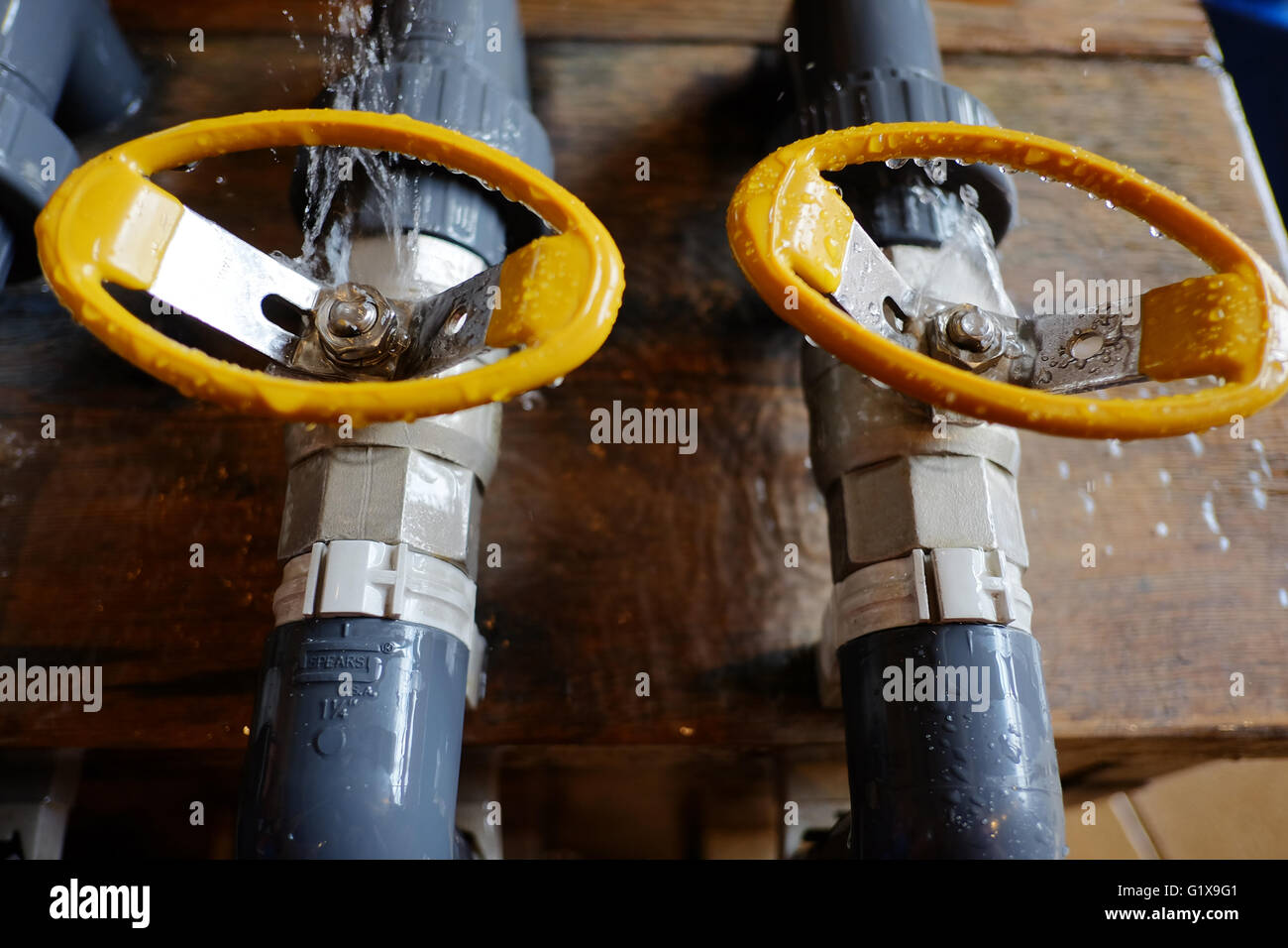 Bright yellow valves on PVC water pipes against a wooden backdrop Stock ...