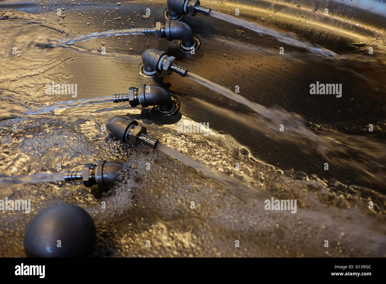 Clean water being sprayed in opposite directions into a basin from ...