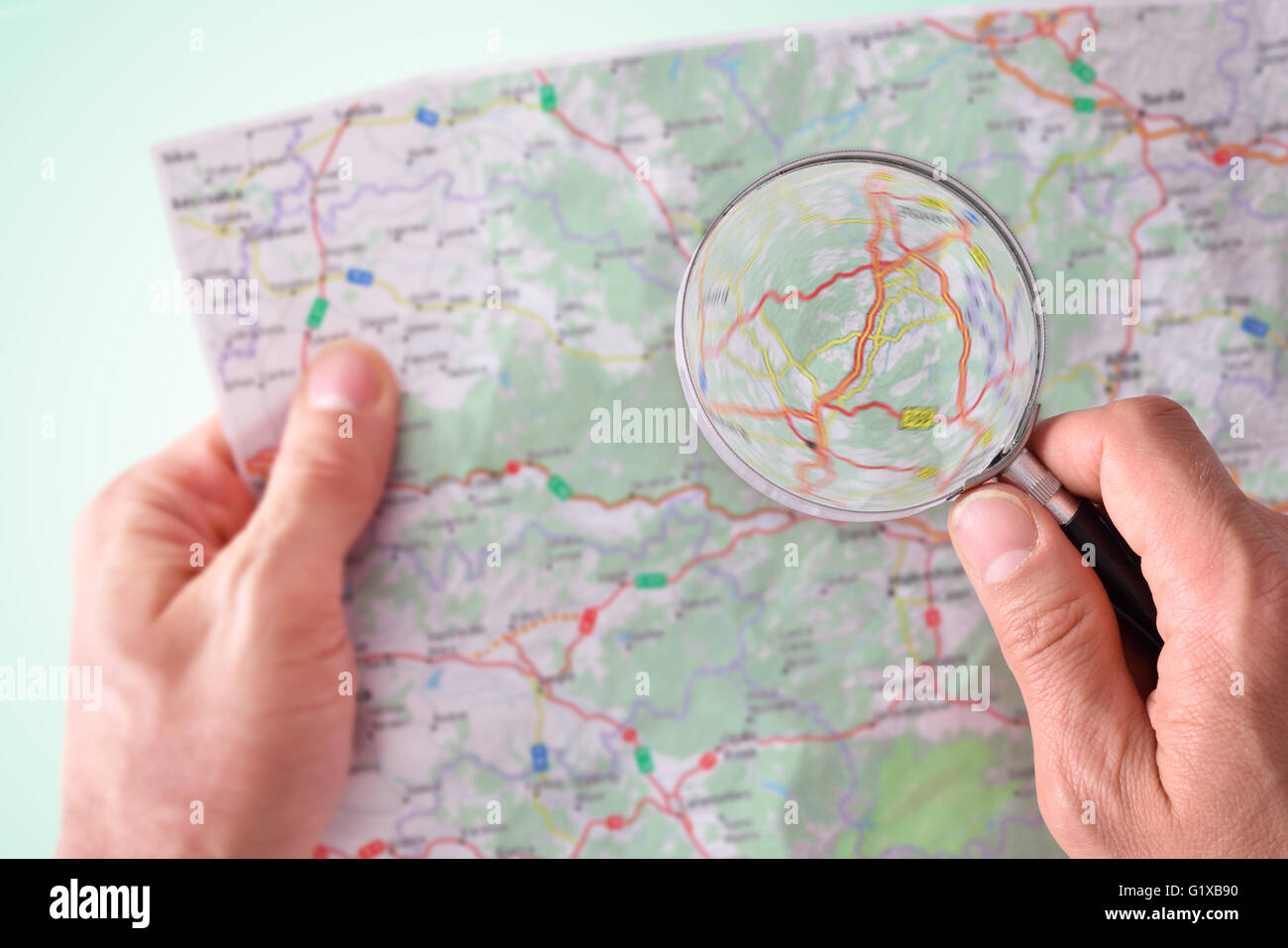 Hands picking up a map and looking for a location with a magnifying ...
