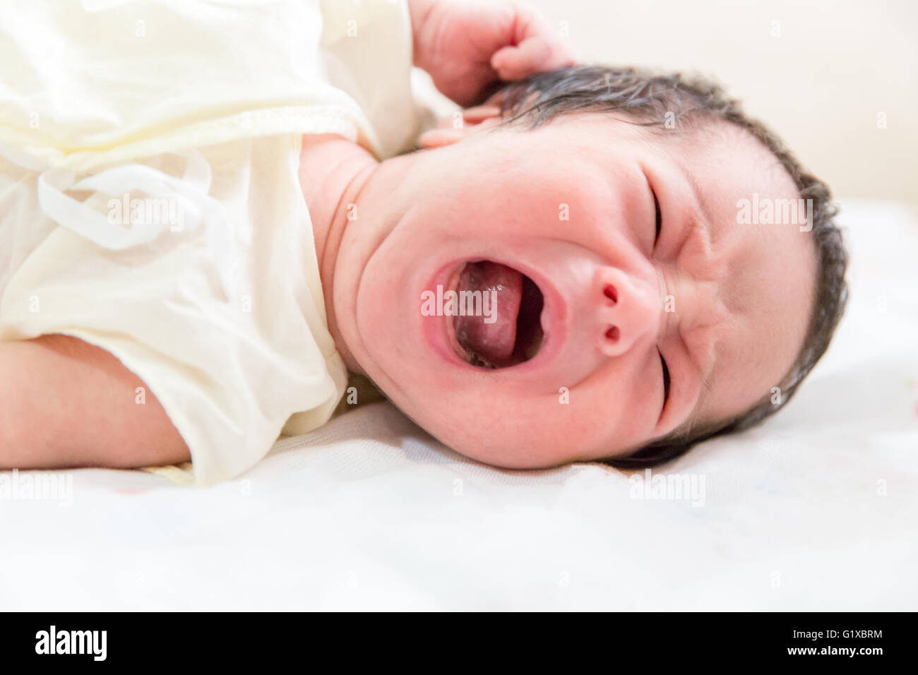 newborn baby crying in her bed Stock Photo - Alamy
