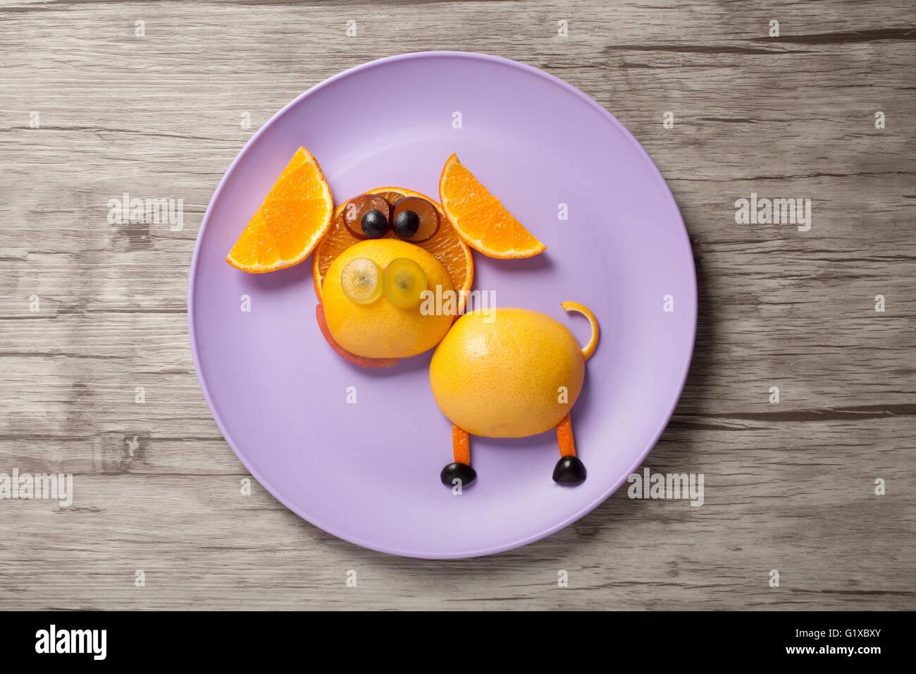 Funny pig made of orange and grape on plate and wood Stock Photo - Alamy