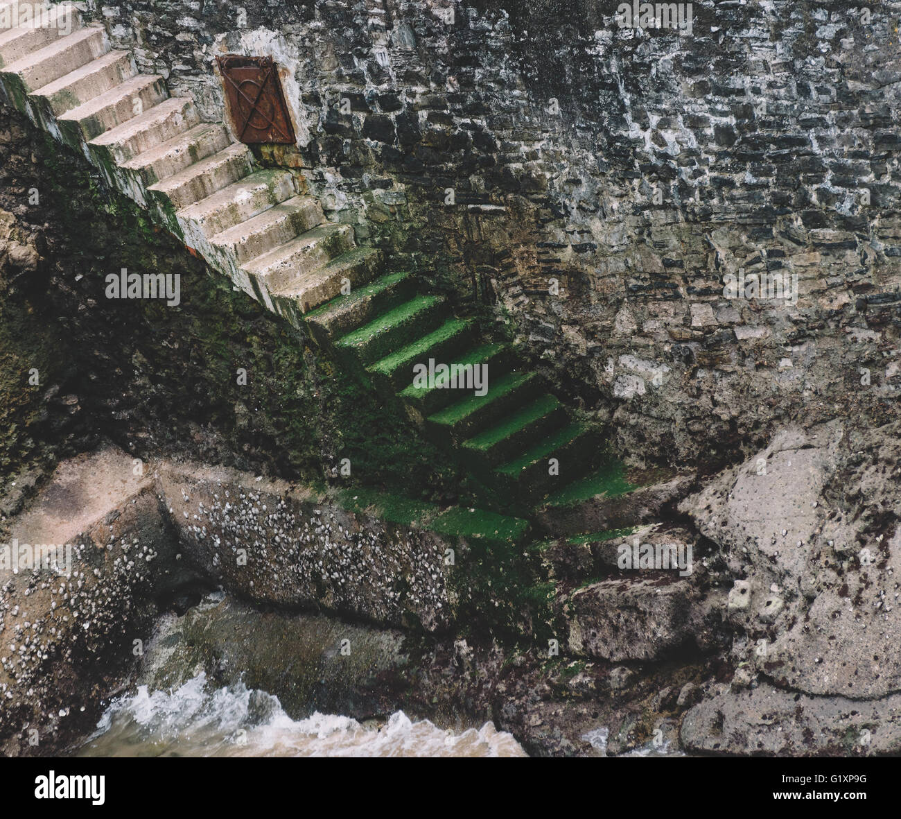 Concrete stairs against a stone wall leading to sea level Stock Photo ...